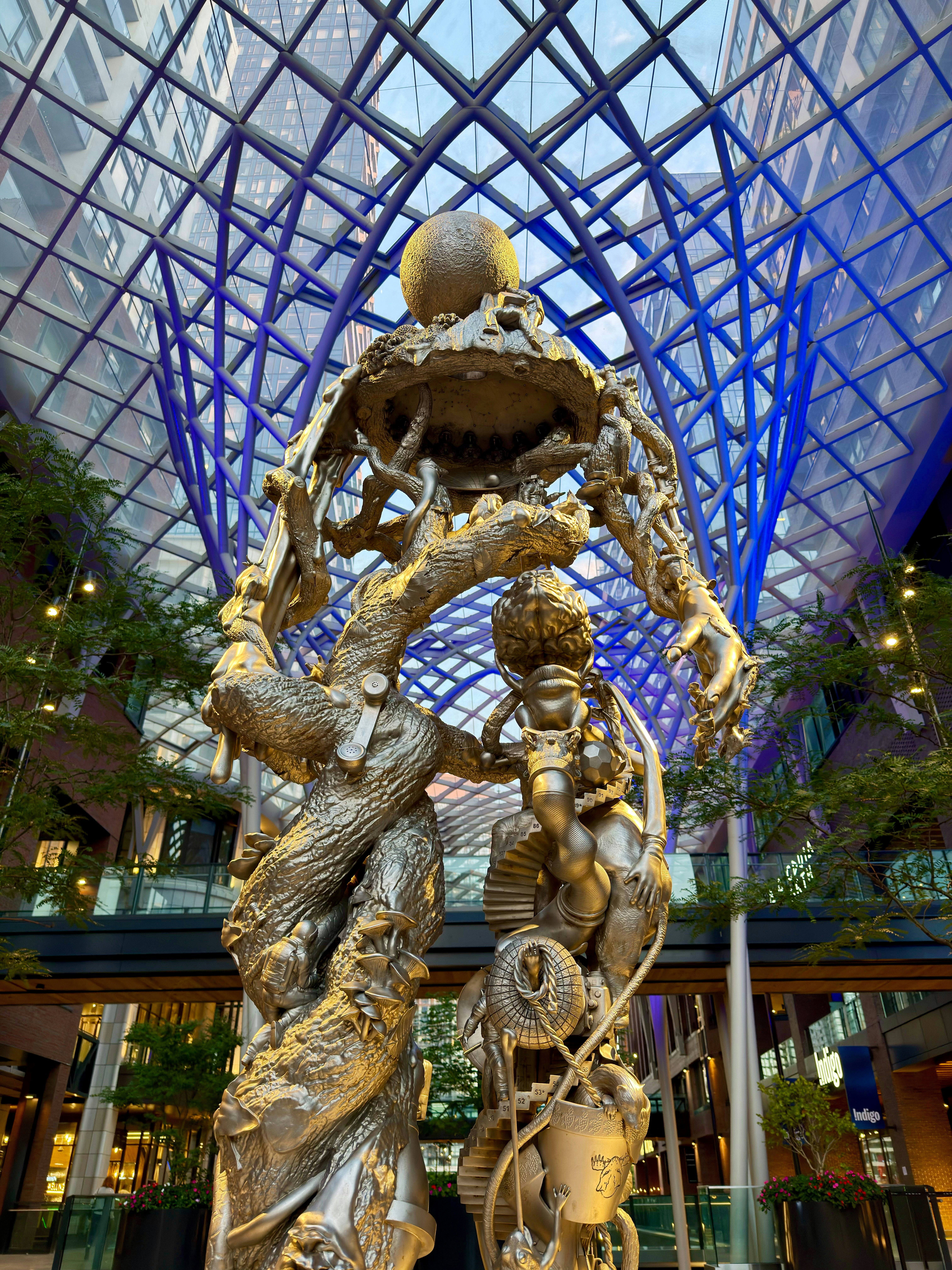 Bronze sculpture crowned by a golden globe under a blue arched glass canopy