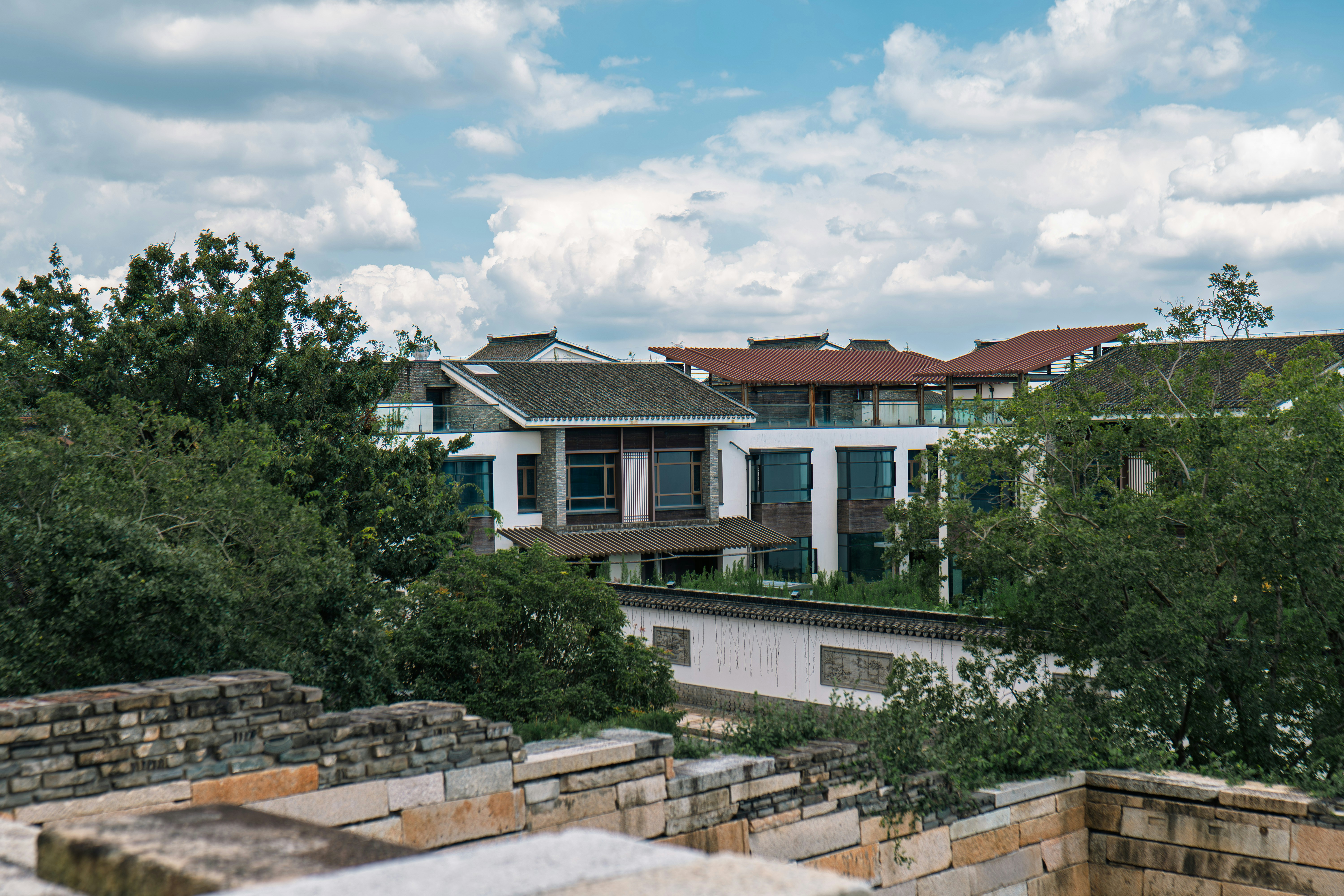 Quiet Courtyard Facade: A Pan-Asian Campus Building with Turquoise Windows and Stone Terrace