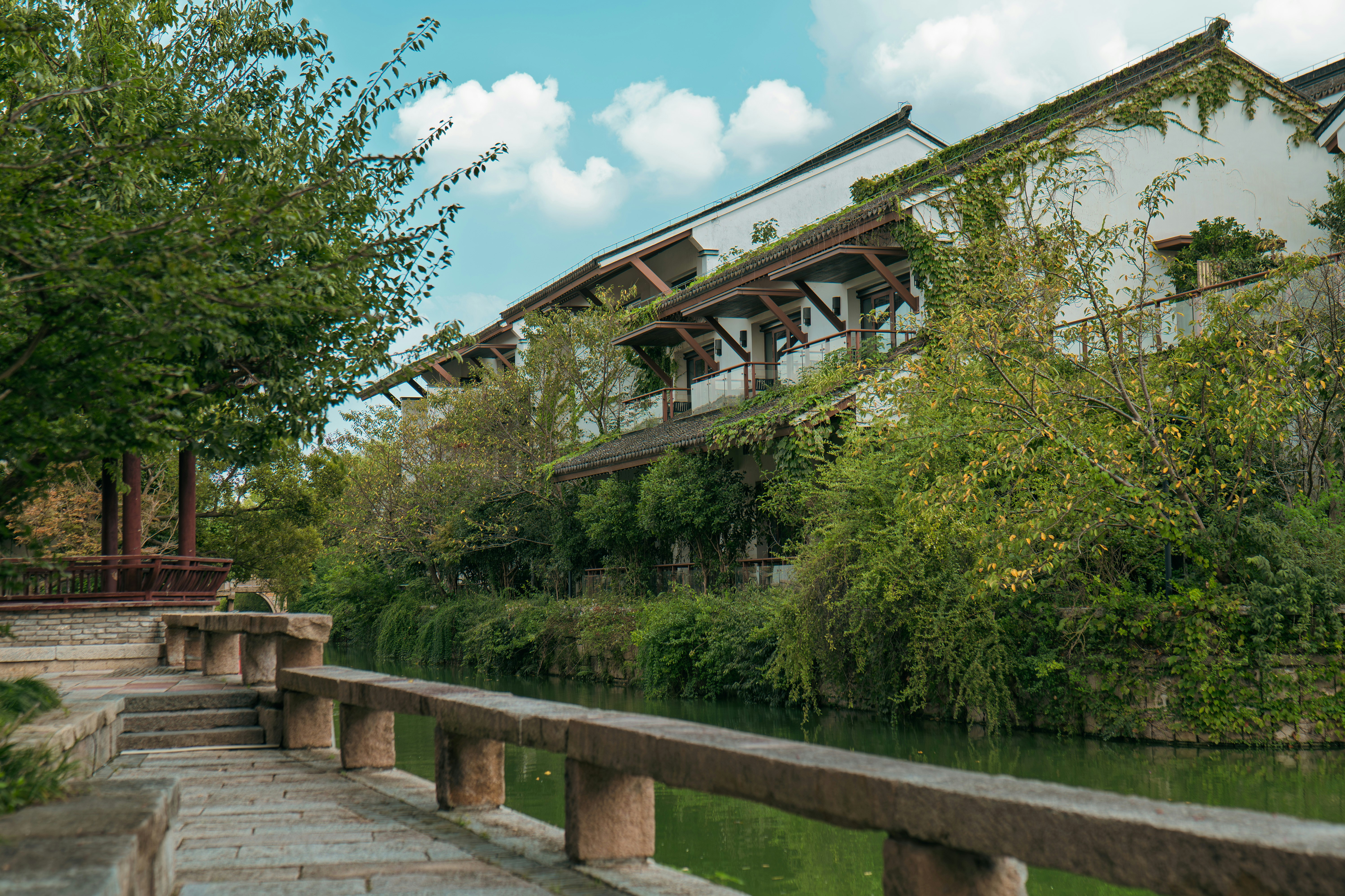 Waterway Walkway: A Traditional Riverside Scene with Leaning House and Lush Foliage