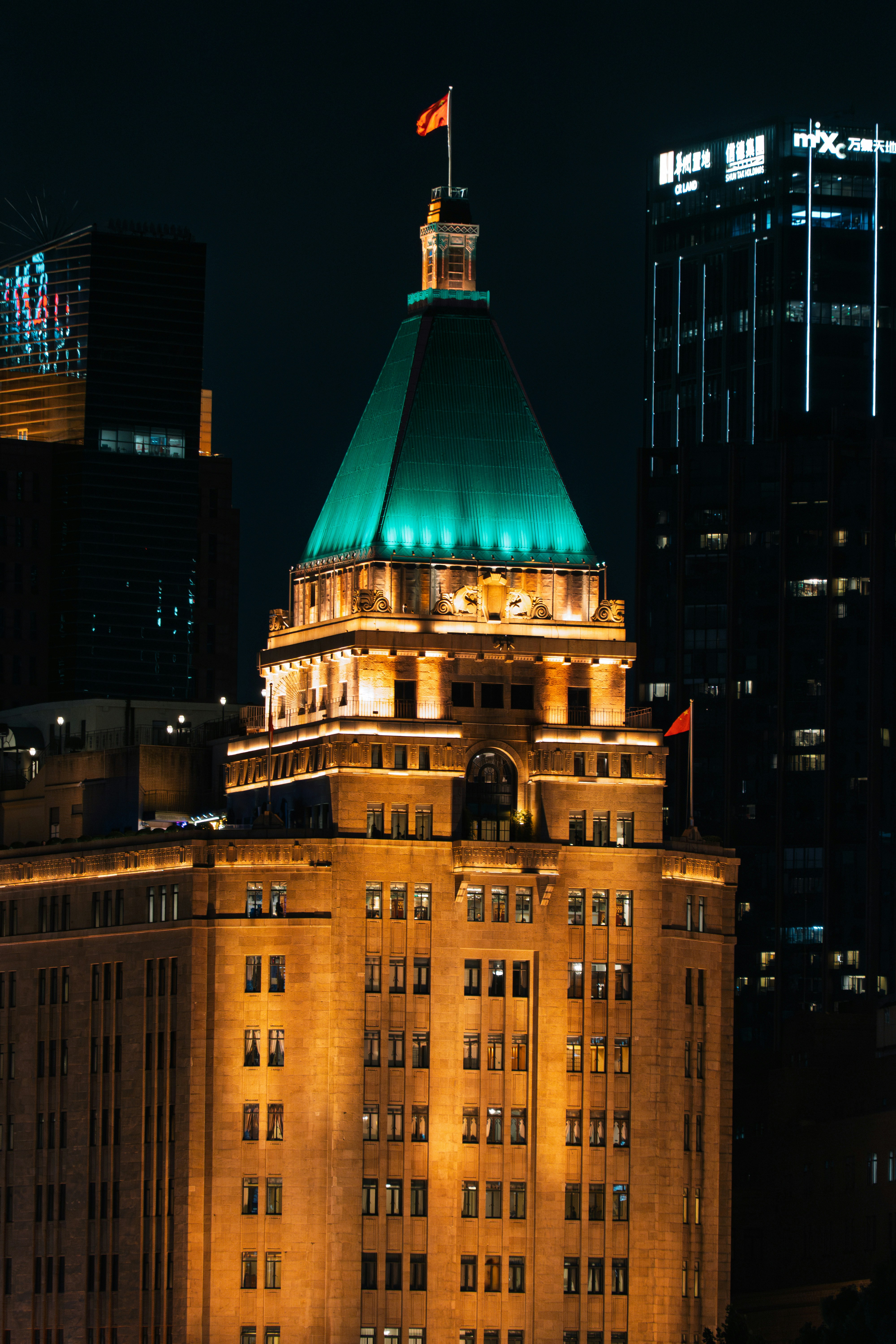 Beaming Turret: Nighttime Duo of a Green-Capped Tower Rising Above a Golden Facade