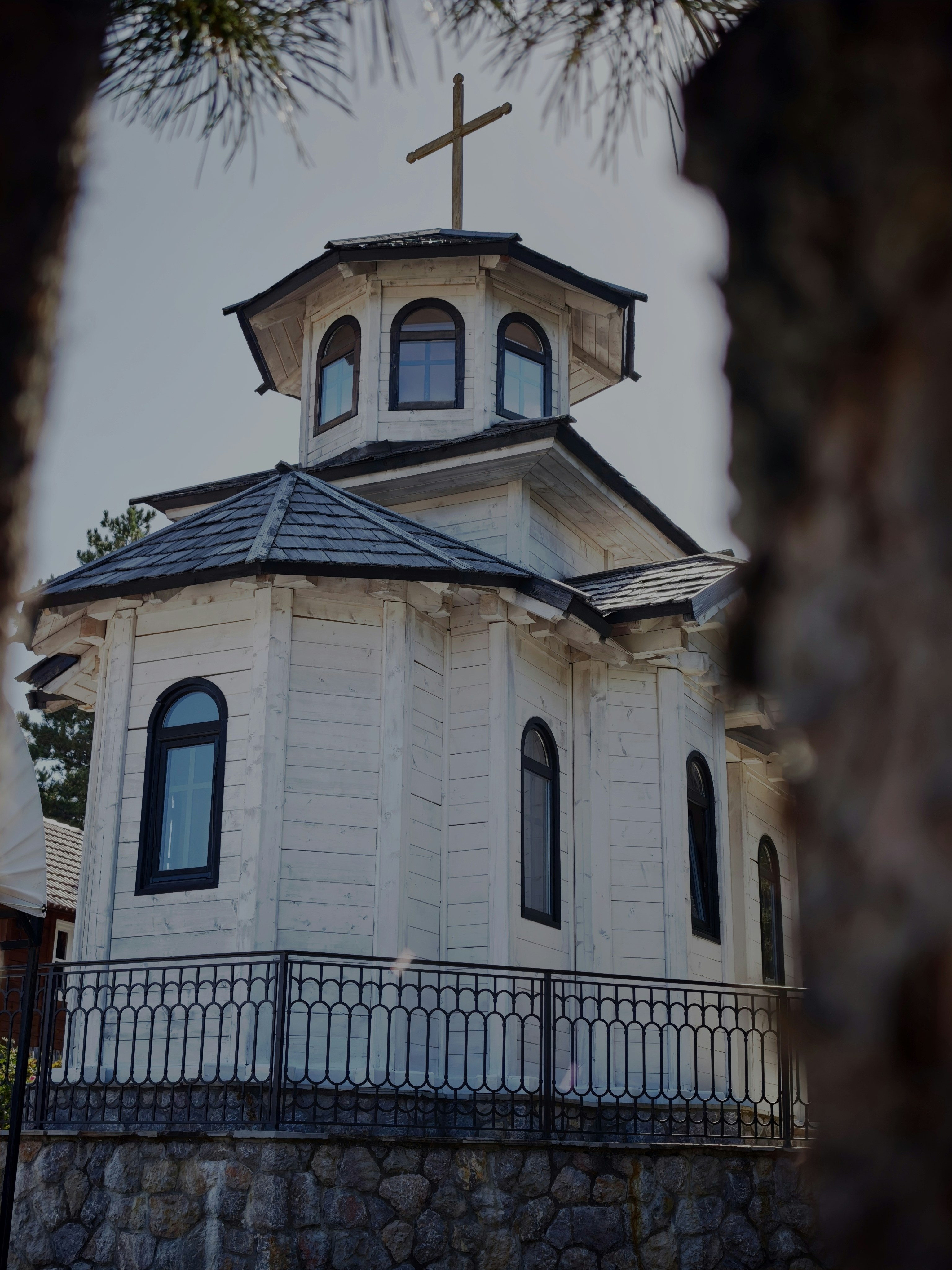 White Chapel on a Stone Base Peeking Through Frame of Trees