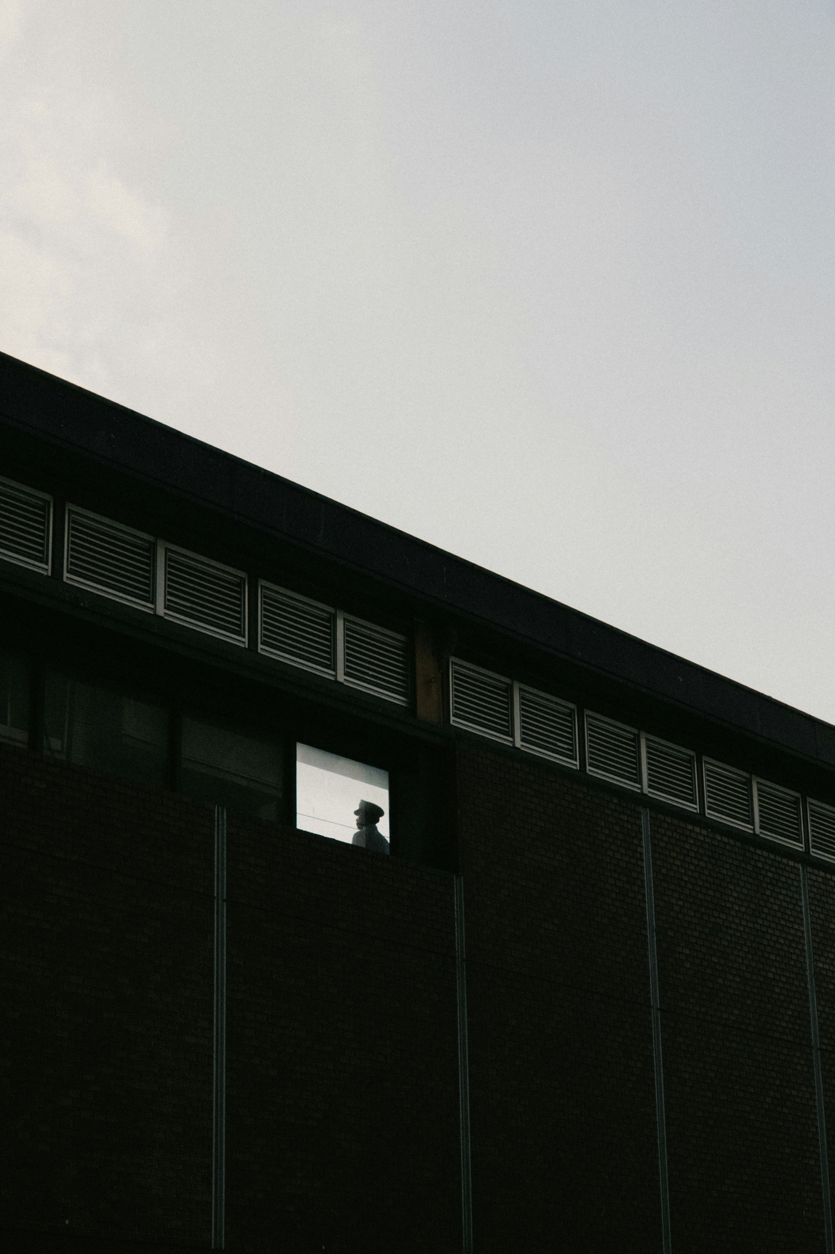 Window of Silence: A Lone Silhouette in the Industrial Ridge