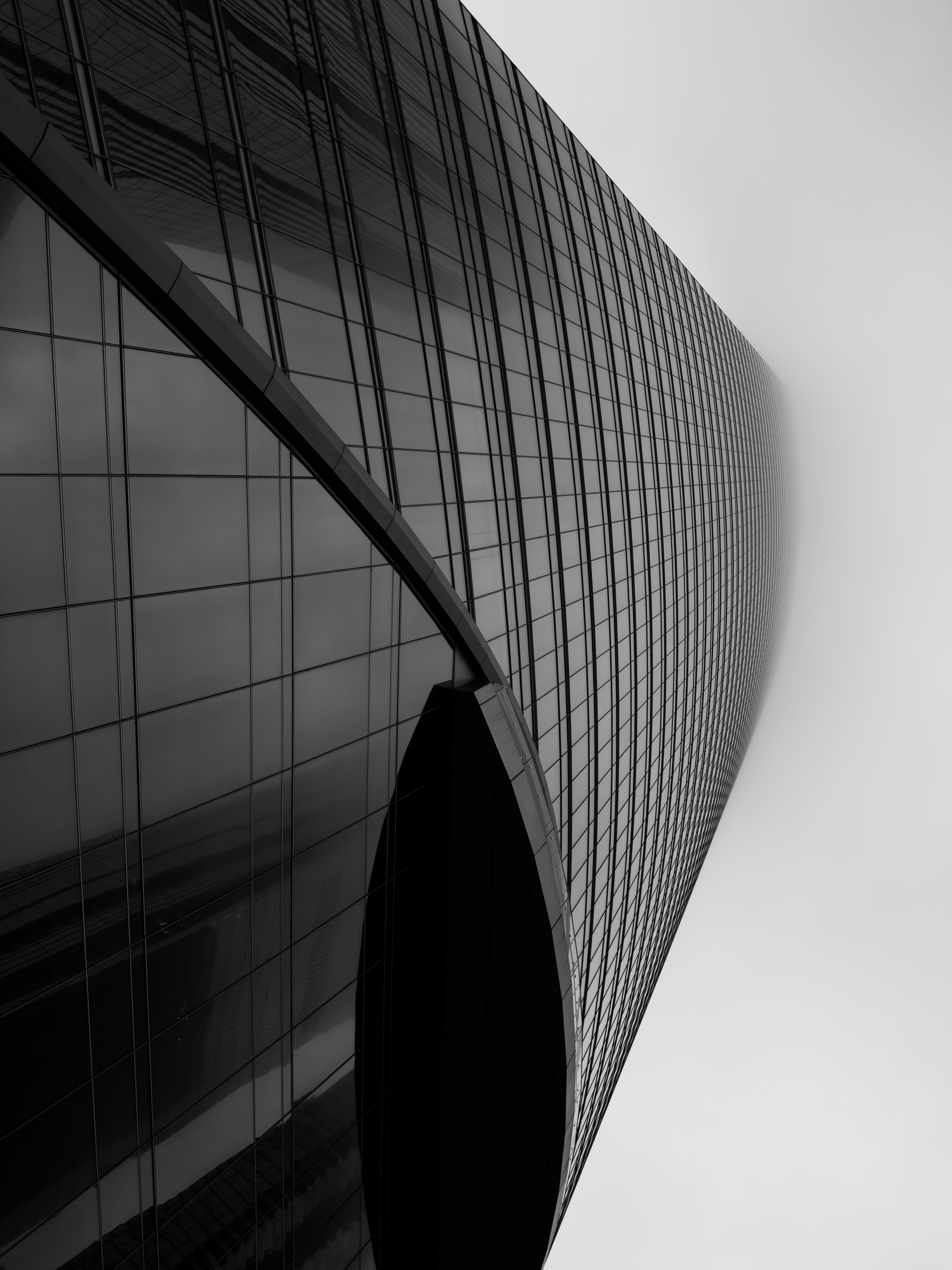 Curved Glass and Sky: A Monochrome Facade Reaches Skyward