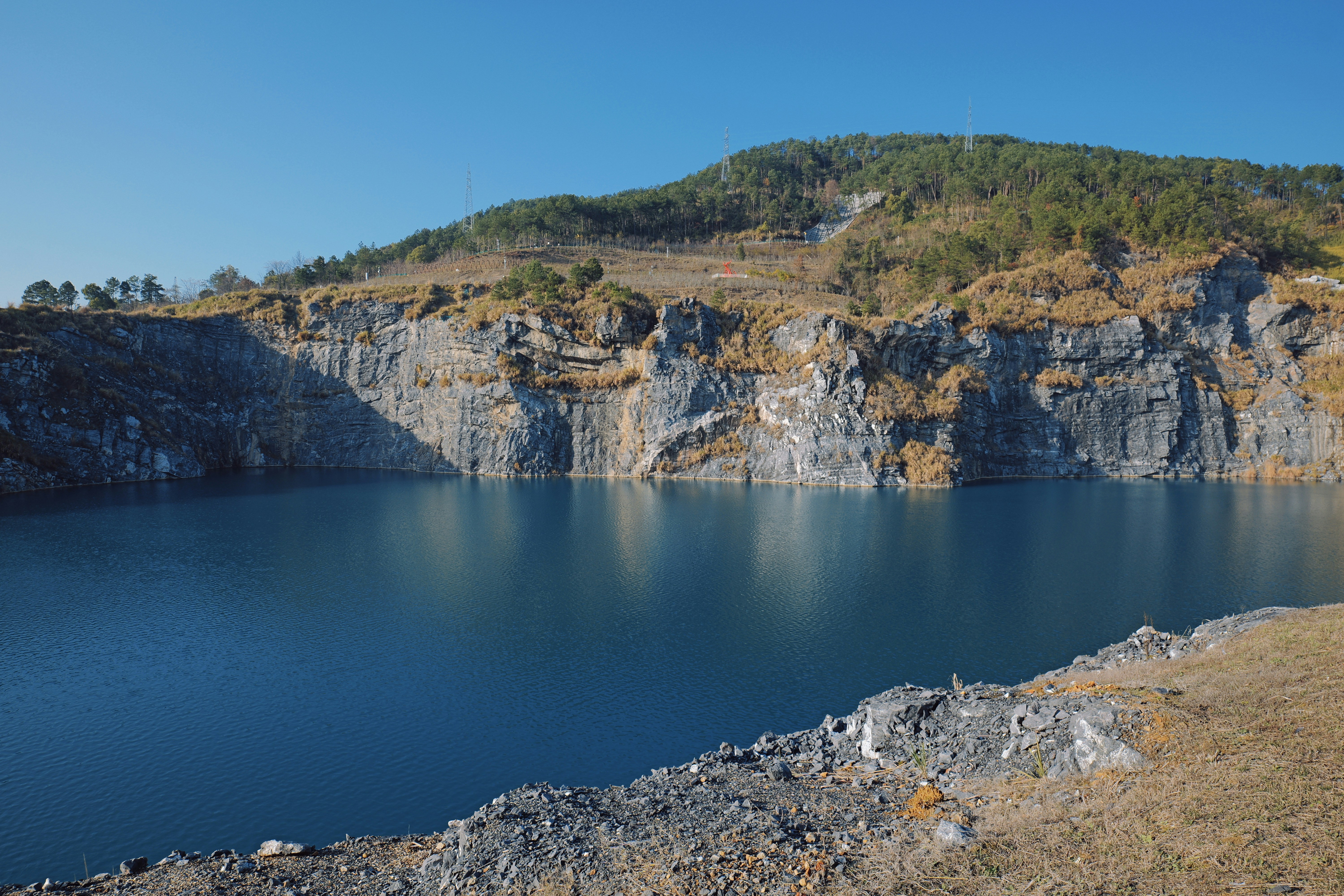 Quiet Blue Quarry: A Sunlit Lake Nestled Between Rocky Rims