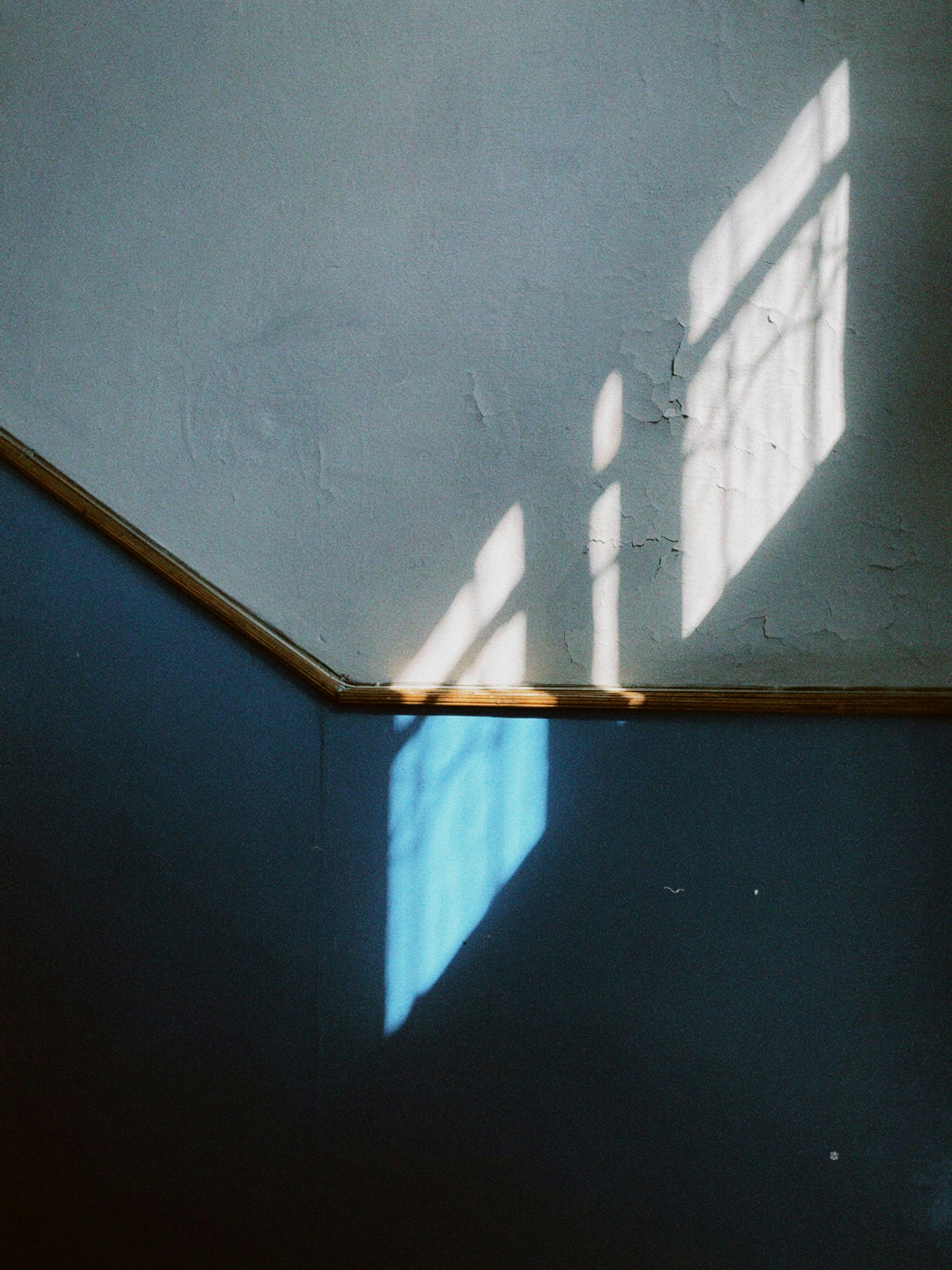 Shadowed Stairwell: A Patchwork of Light on A Worn Wall