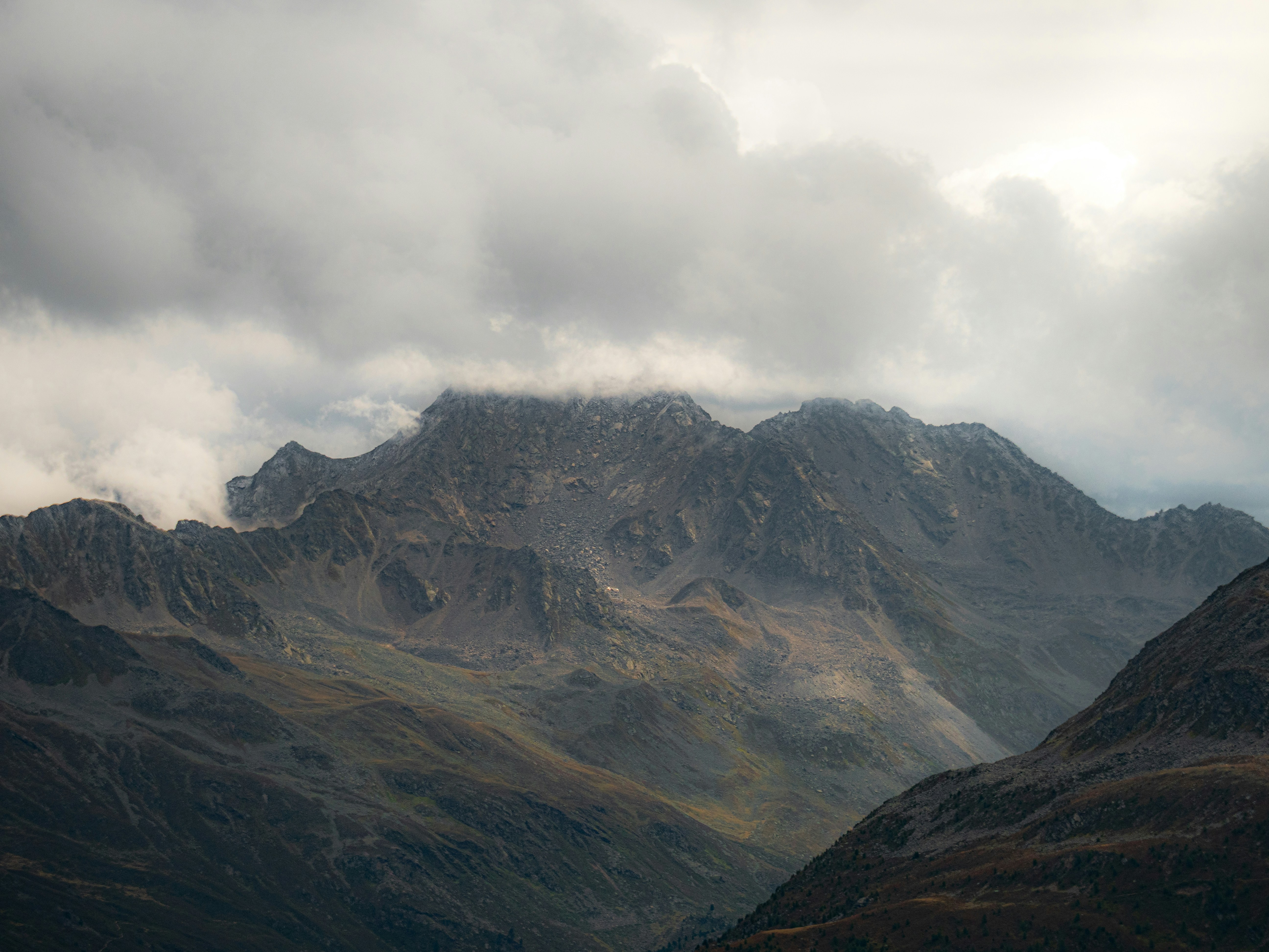 Mist-veiled Peaks: A Rugged Alpine Tapestry Beneath Brooding Clouds