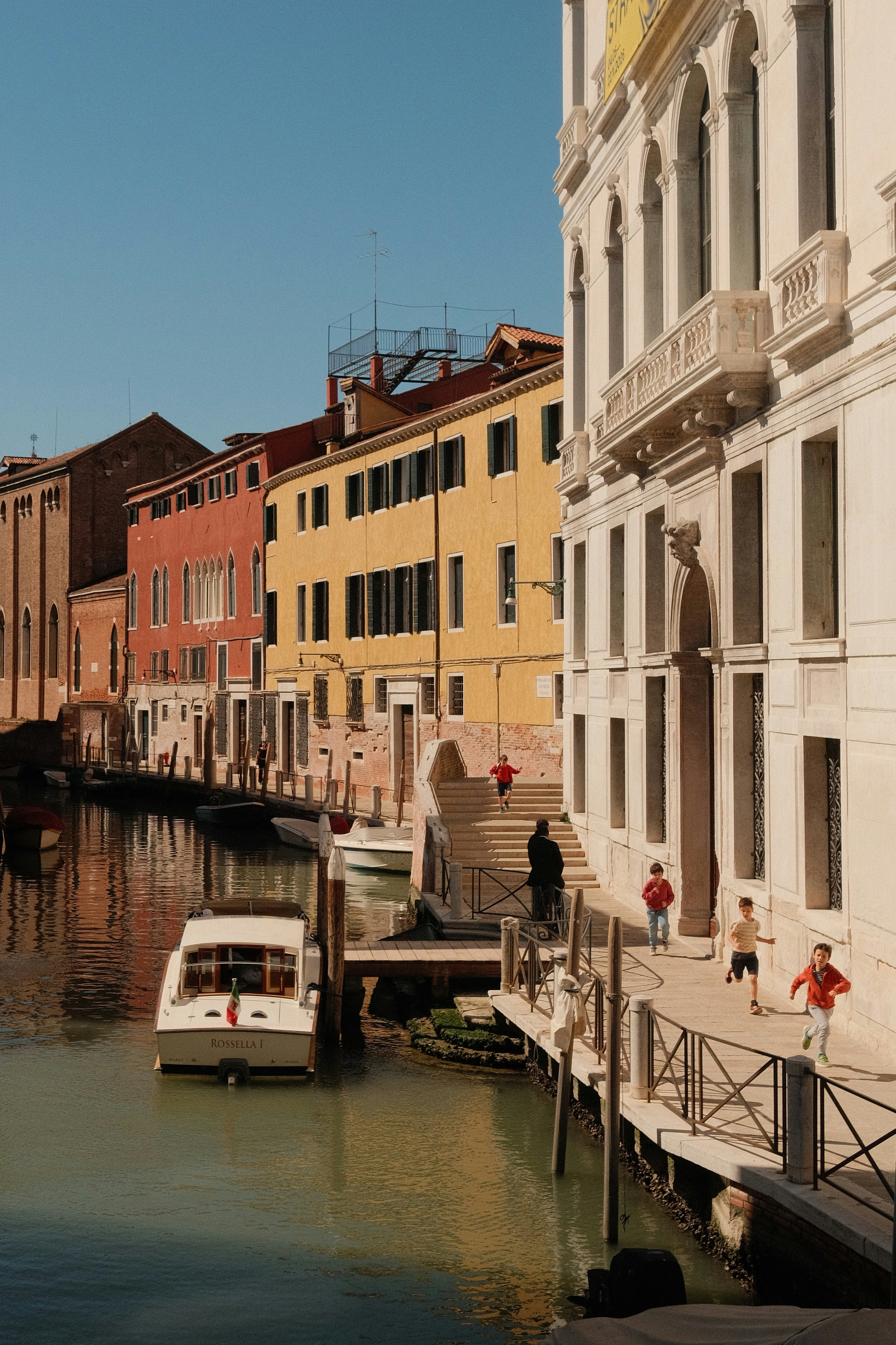 Sunlit Venice-Style Canal with Colorful Façades and Riverside Walk