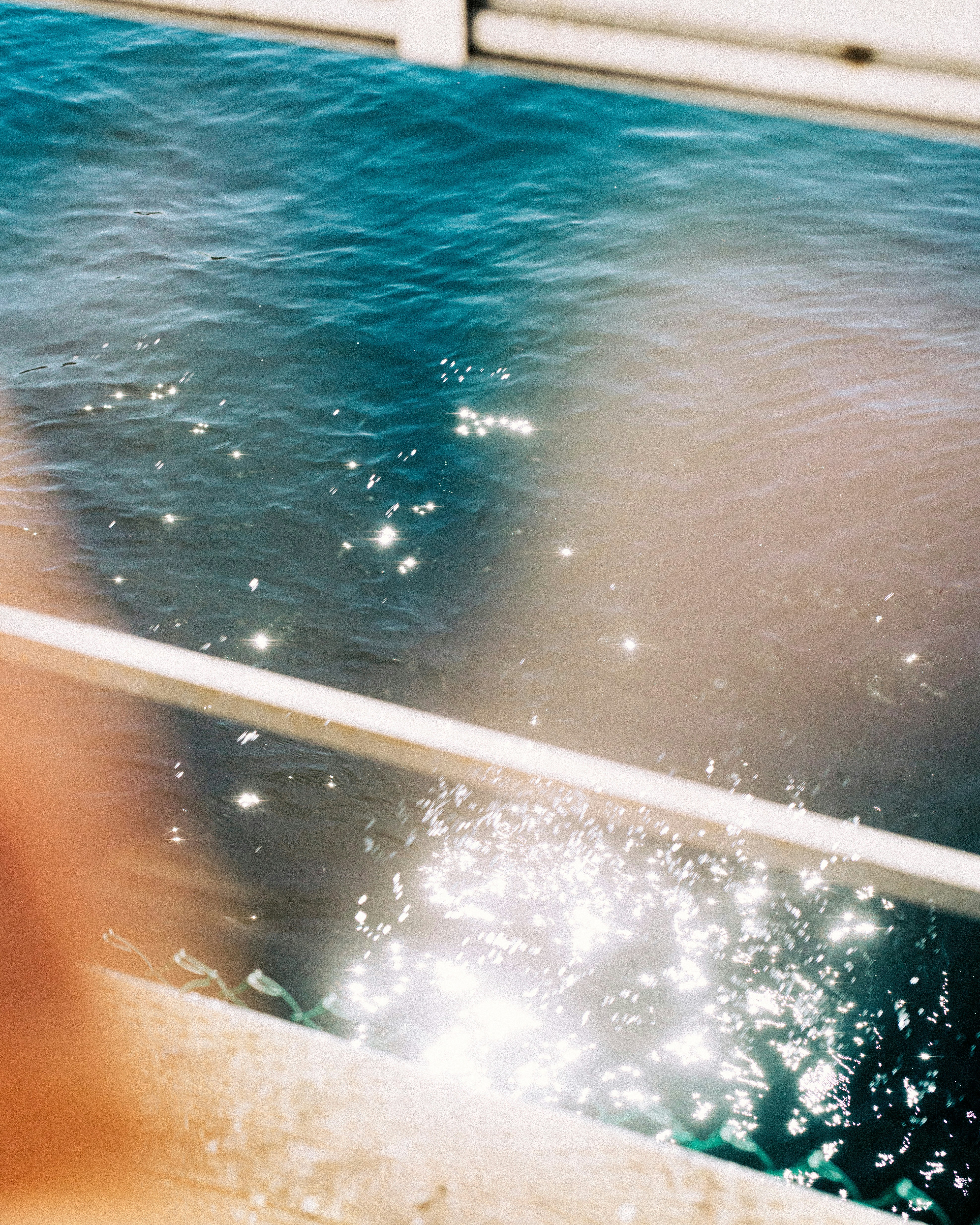 Sunlit Ripples Over Turquoise Water from a Boatside Perspective