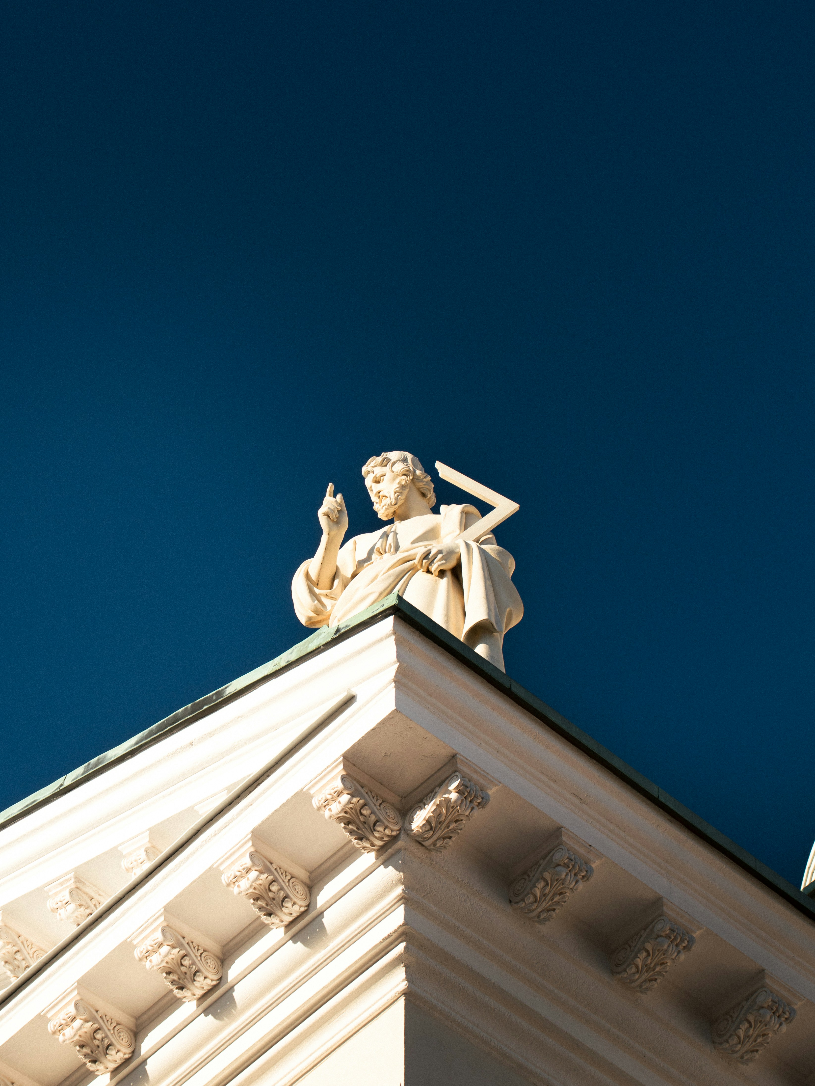 Statue Sentinel on a Cornered Pediment Against a Velvet Sky