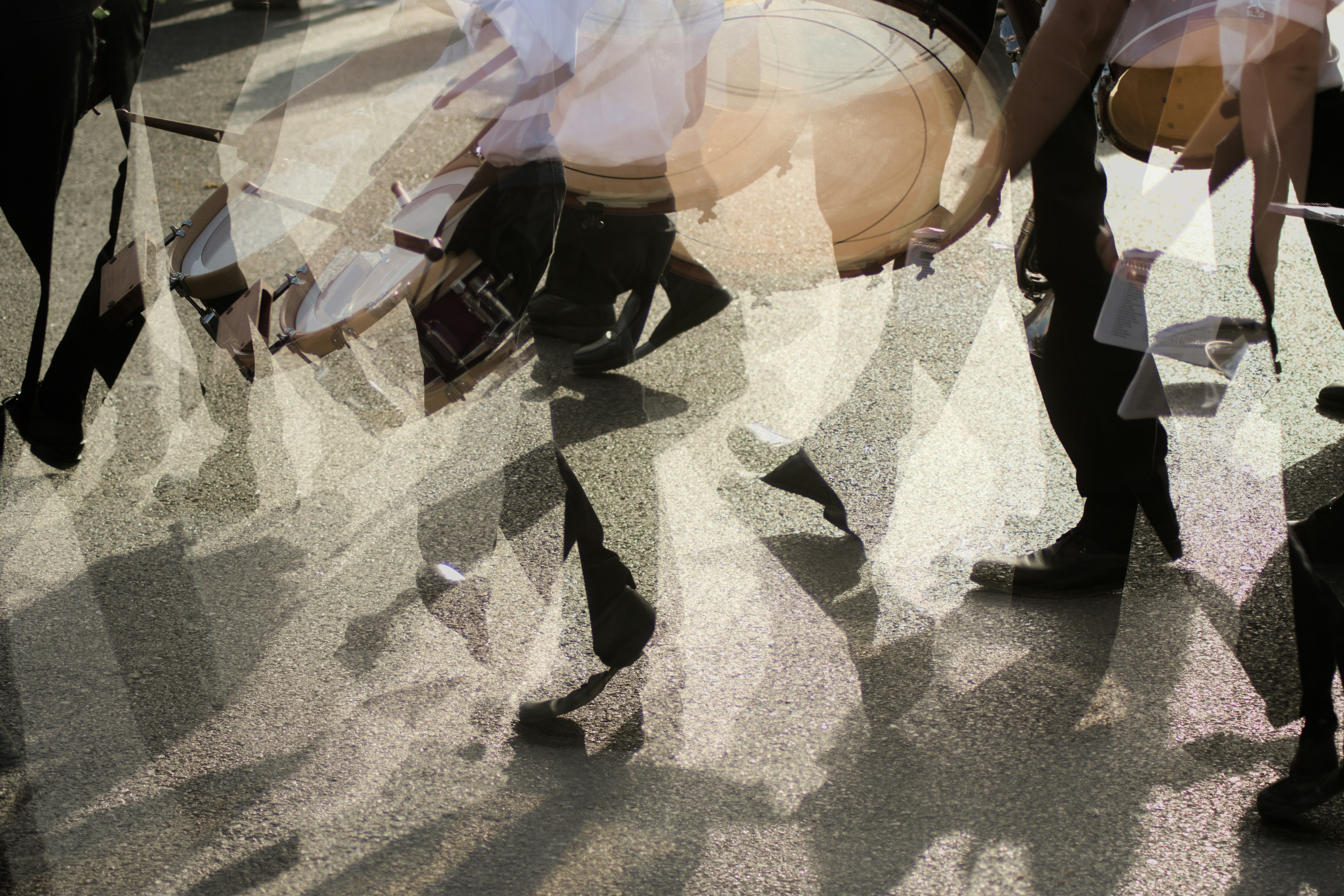 Shadows in Motion: A Crowd of feet and instruments in a sunlit alley