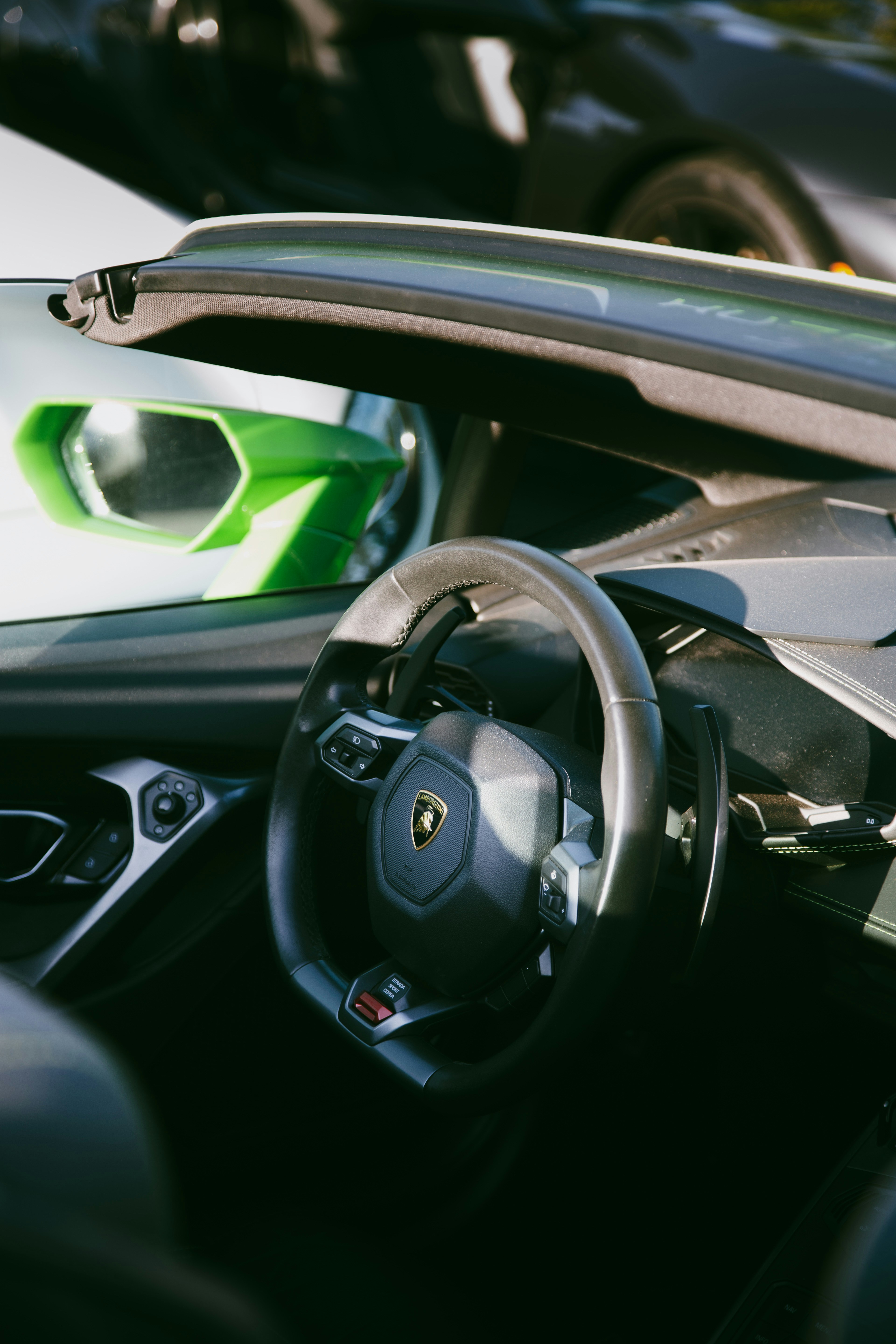 Steering Wheel Spotlight: Lamborghini Cockpit Between Open Roof and Lime Green Car Reflections
