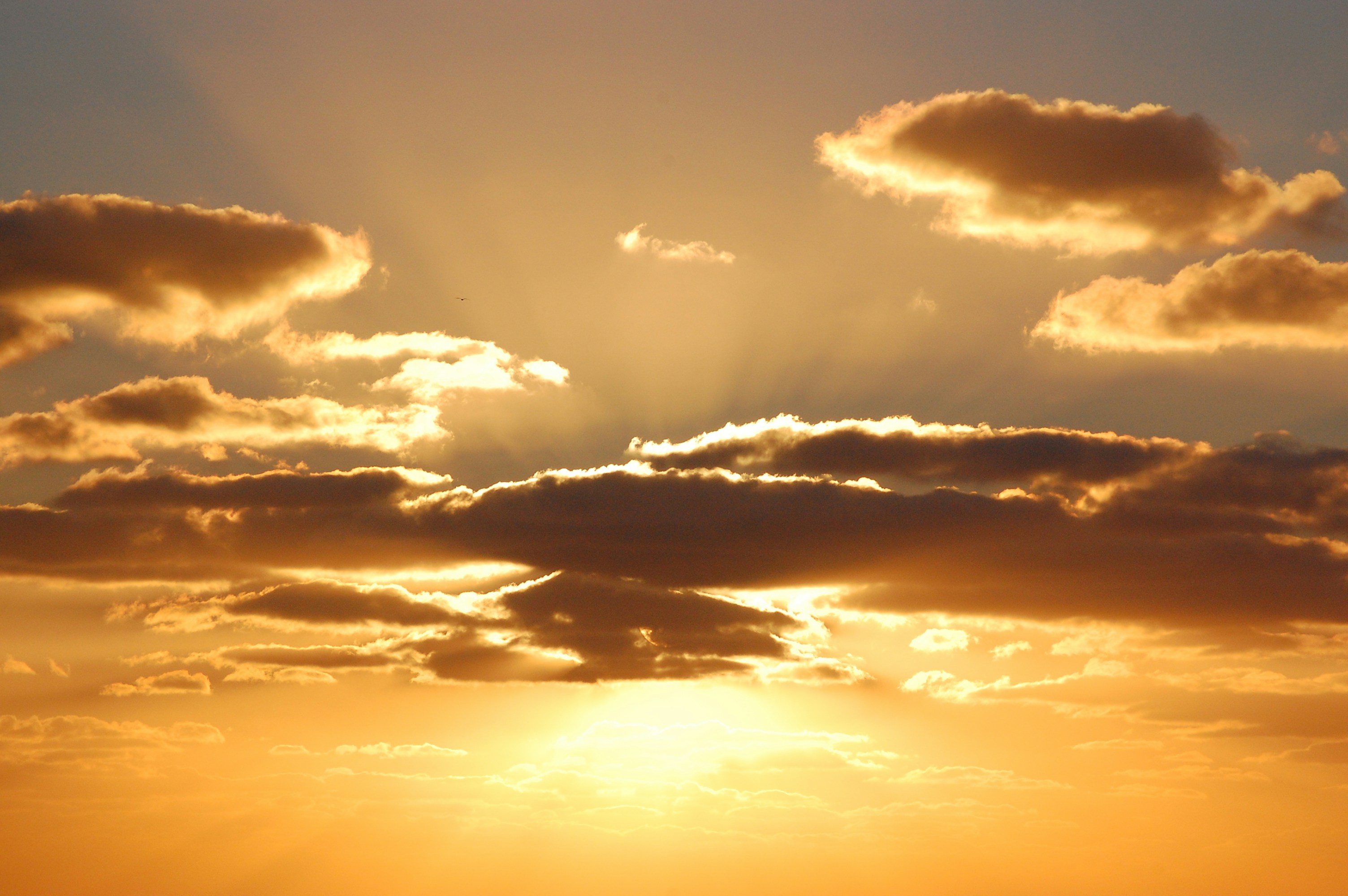 Golden Veil: Radiant Sunset Over Layered Clouds