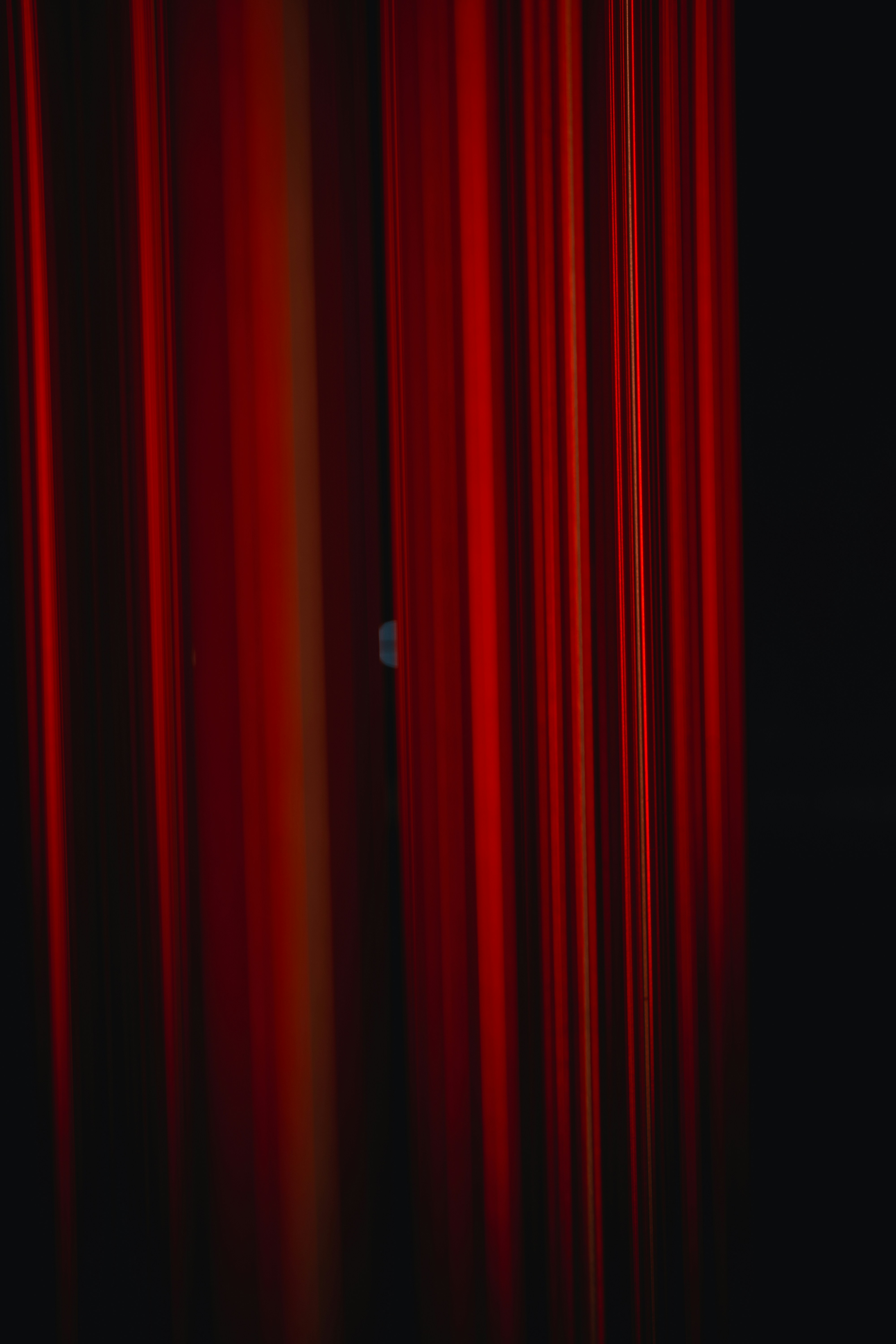 Crimson Veins: Vertical Light Streaks in a Dark Corridor