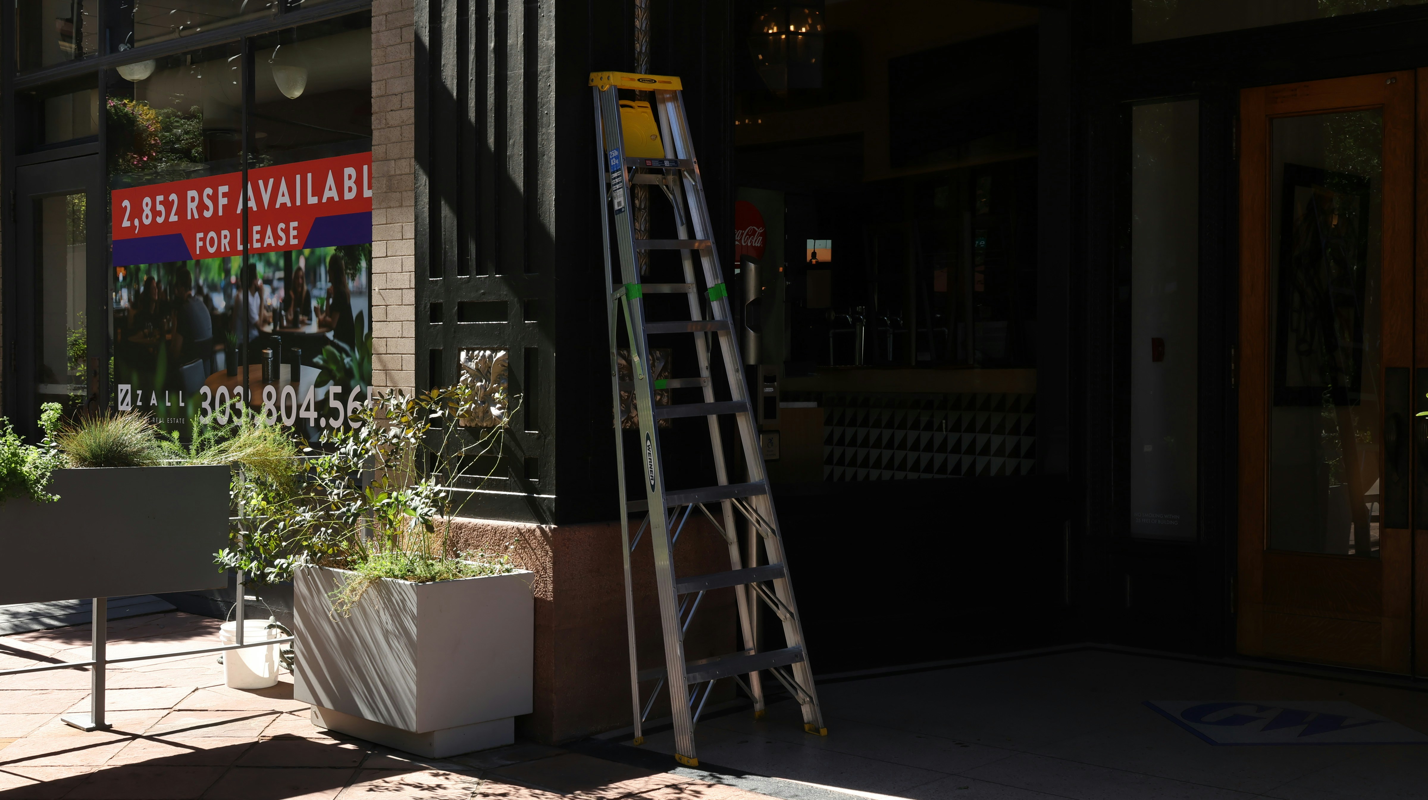 Ladder Against a Dark Shopfront: Quiet City Sidewalk Scene