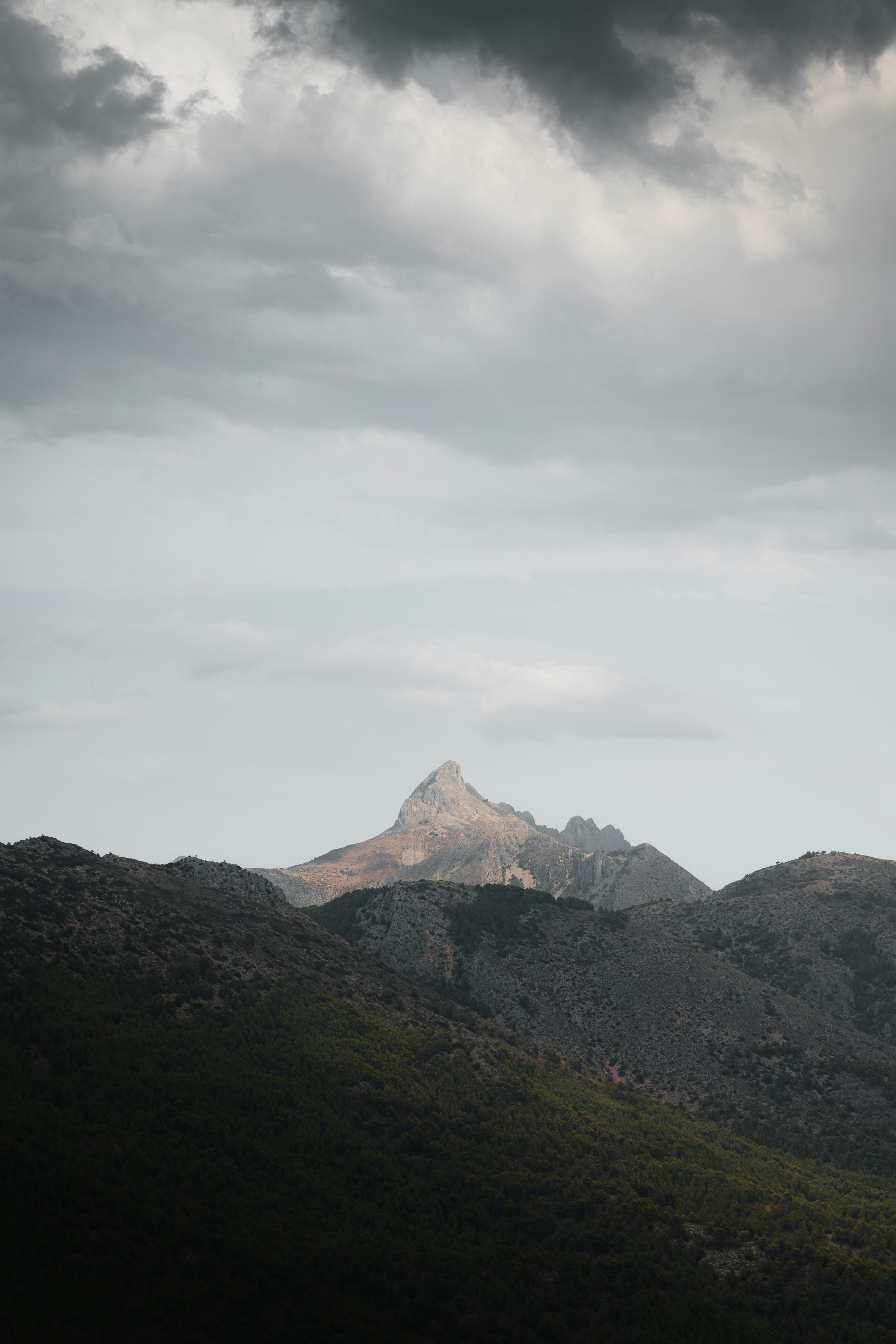 Sunlit Peak Emerging from a Cloud-Elevated Range