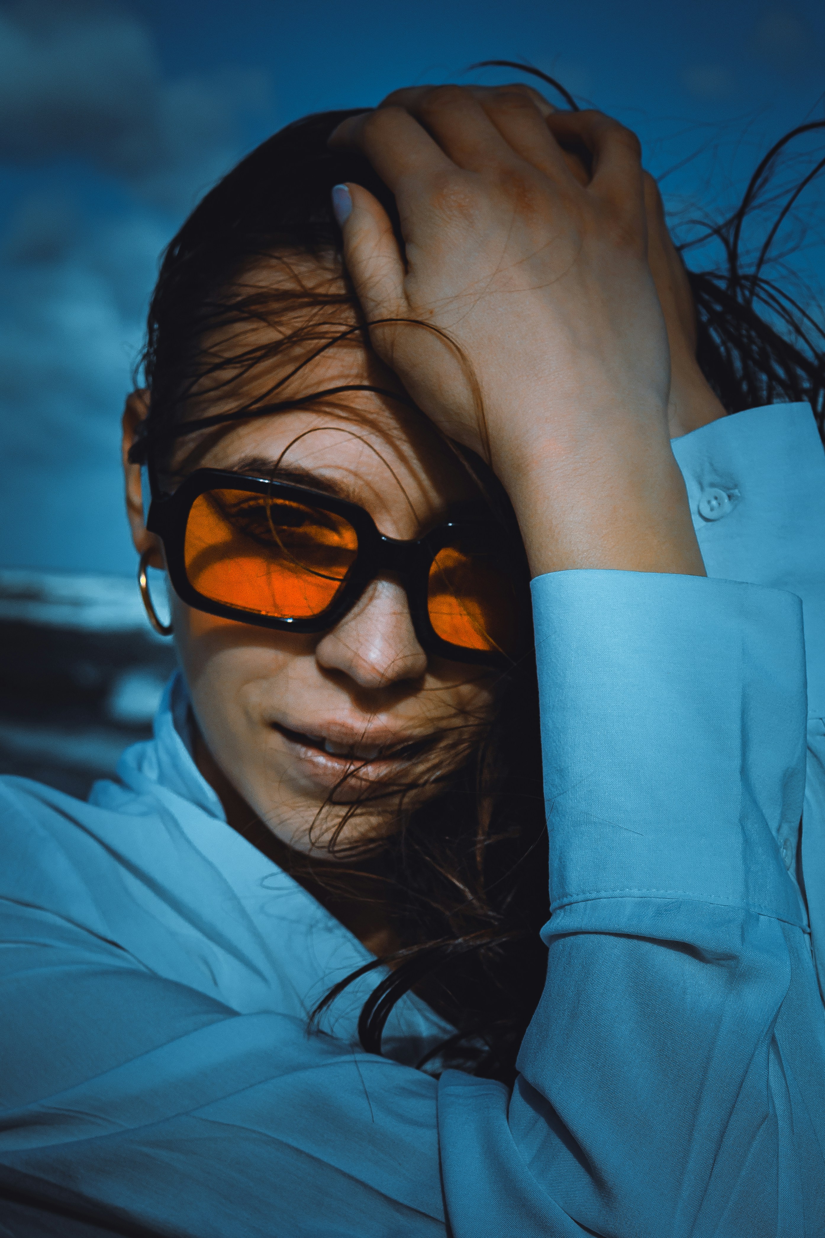 Wind-swept Portrait in Crisp Blue Jeans and Orange-tinted Glasses