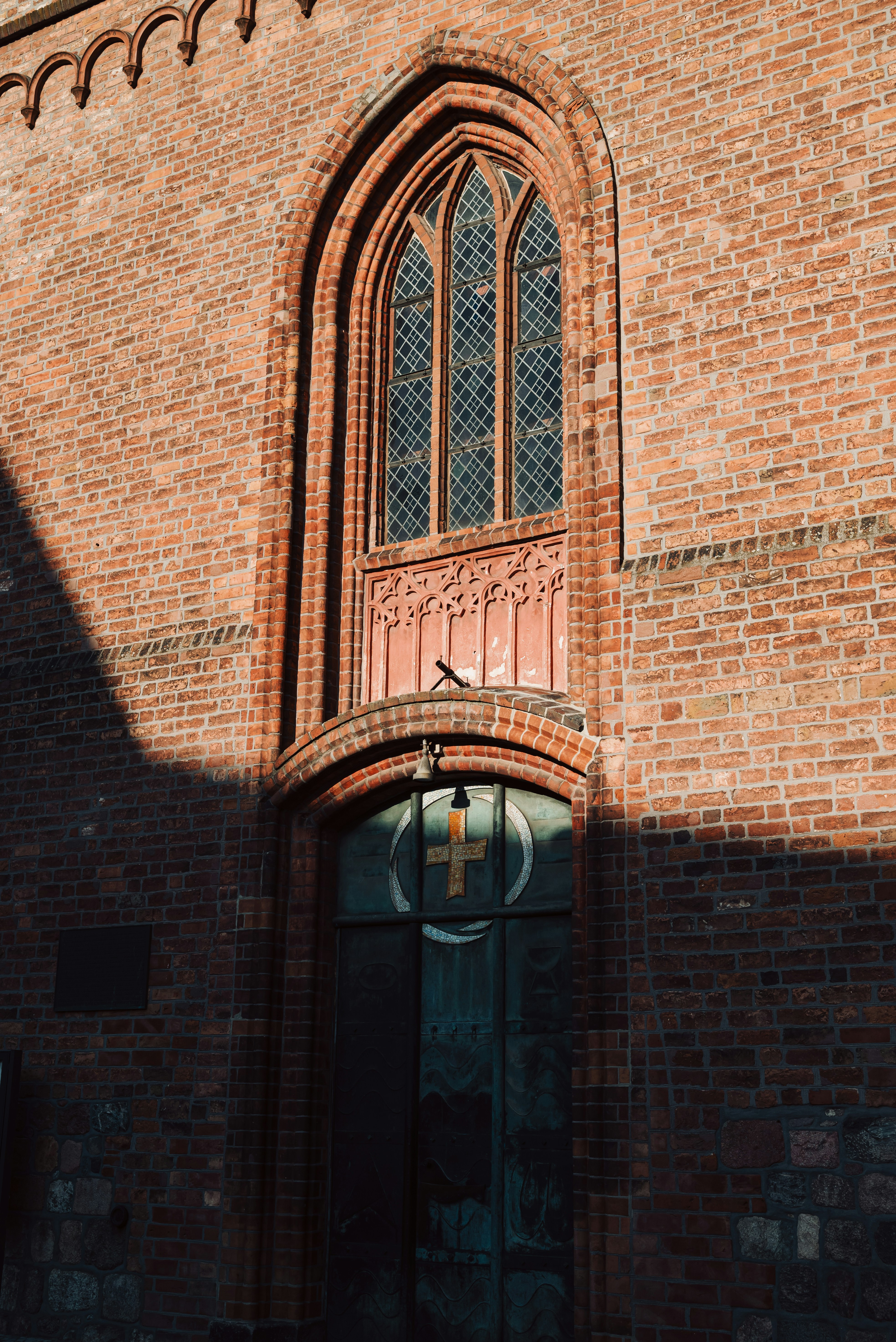 Sunlit Brick Archway and Stained Glass Window Cast in Shadow