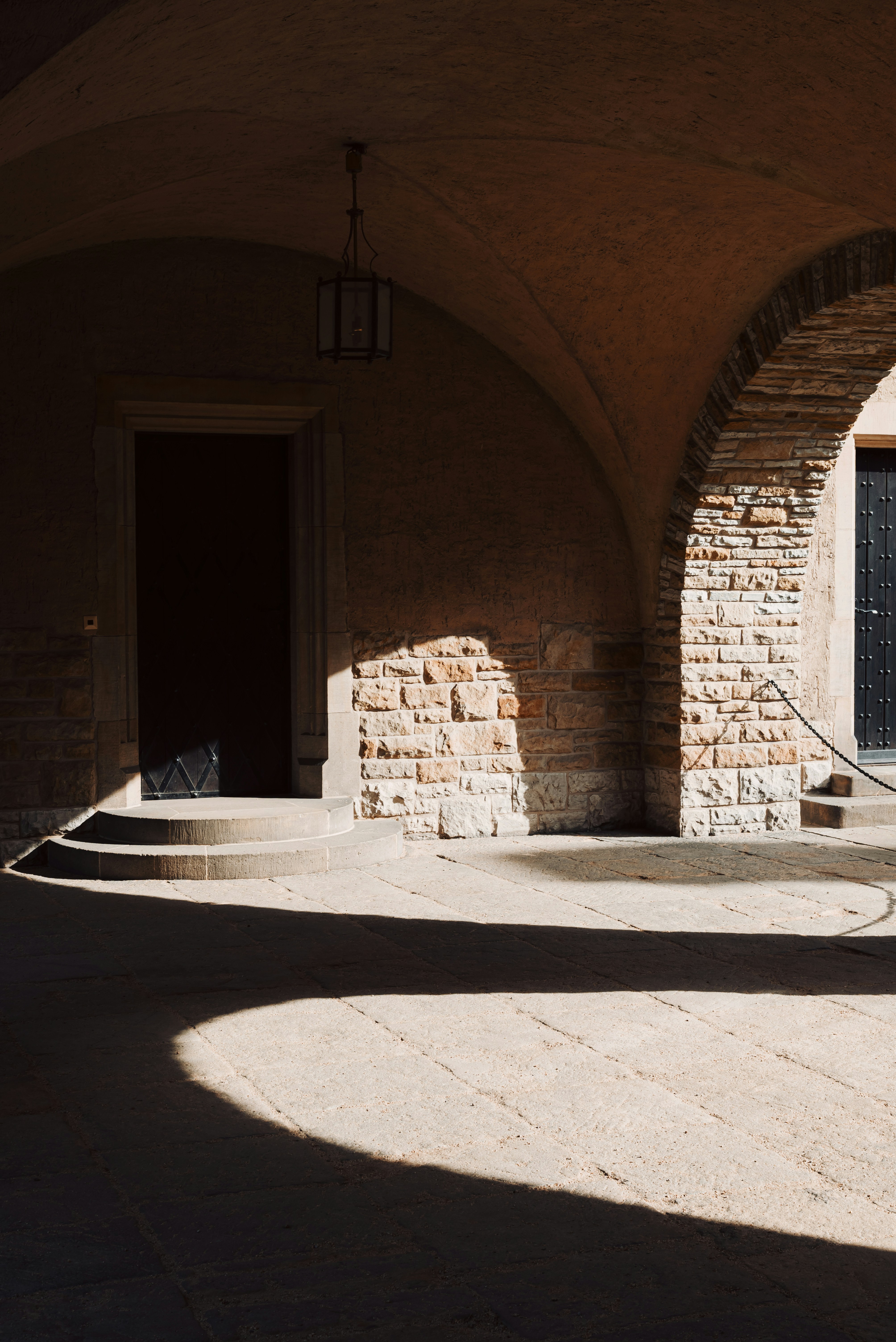 Shadowed Archway: Quiet Doorway Beneath Sunlit Arc