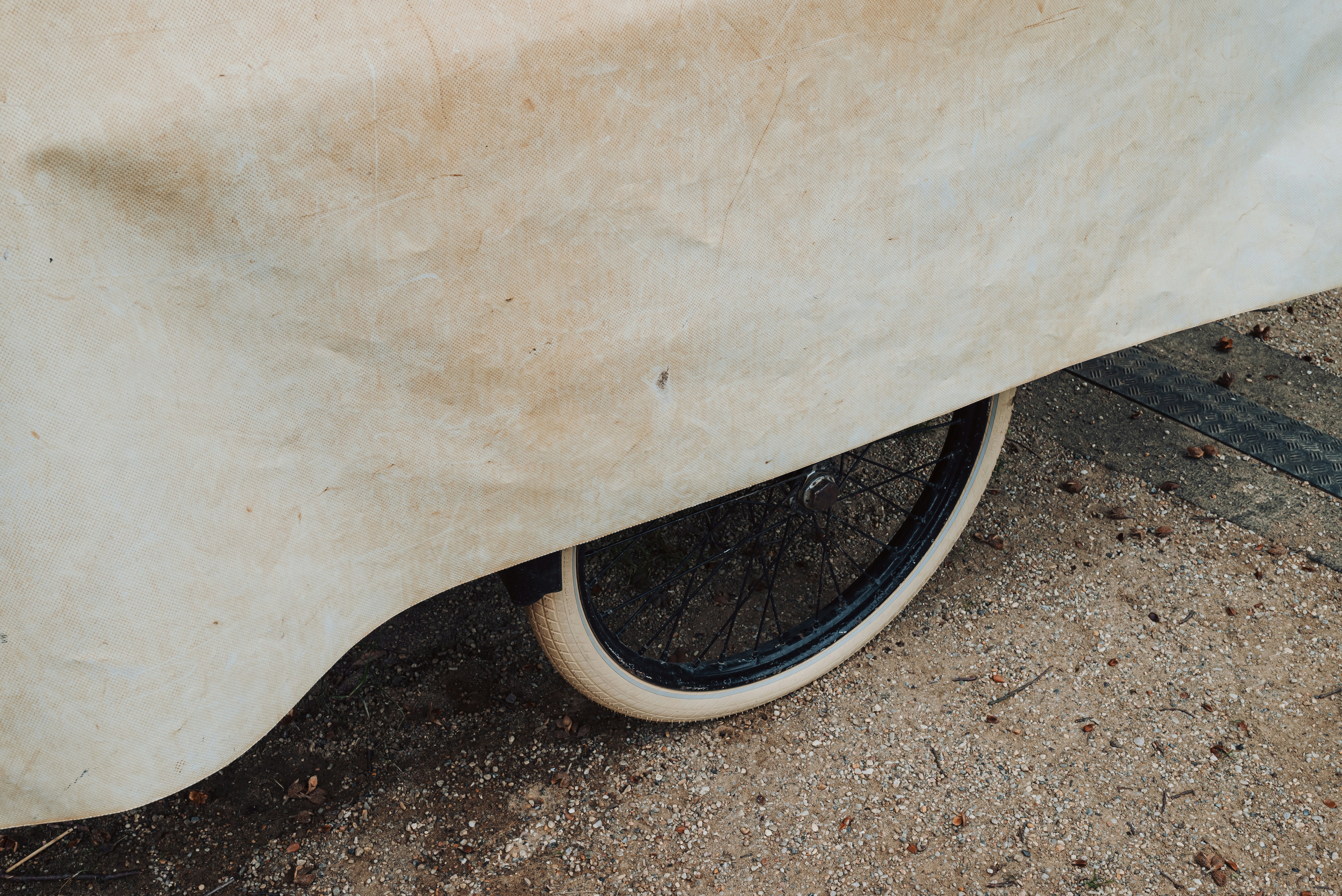 Hidden Wheel Under a Weathered Tarp