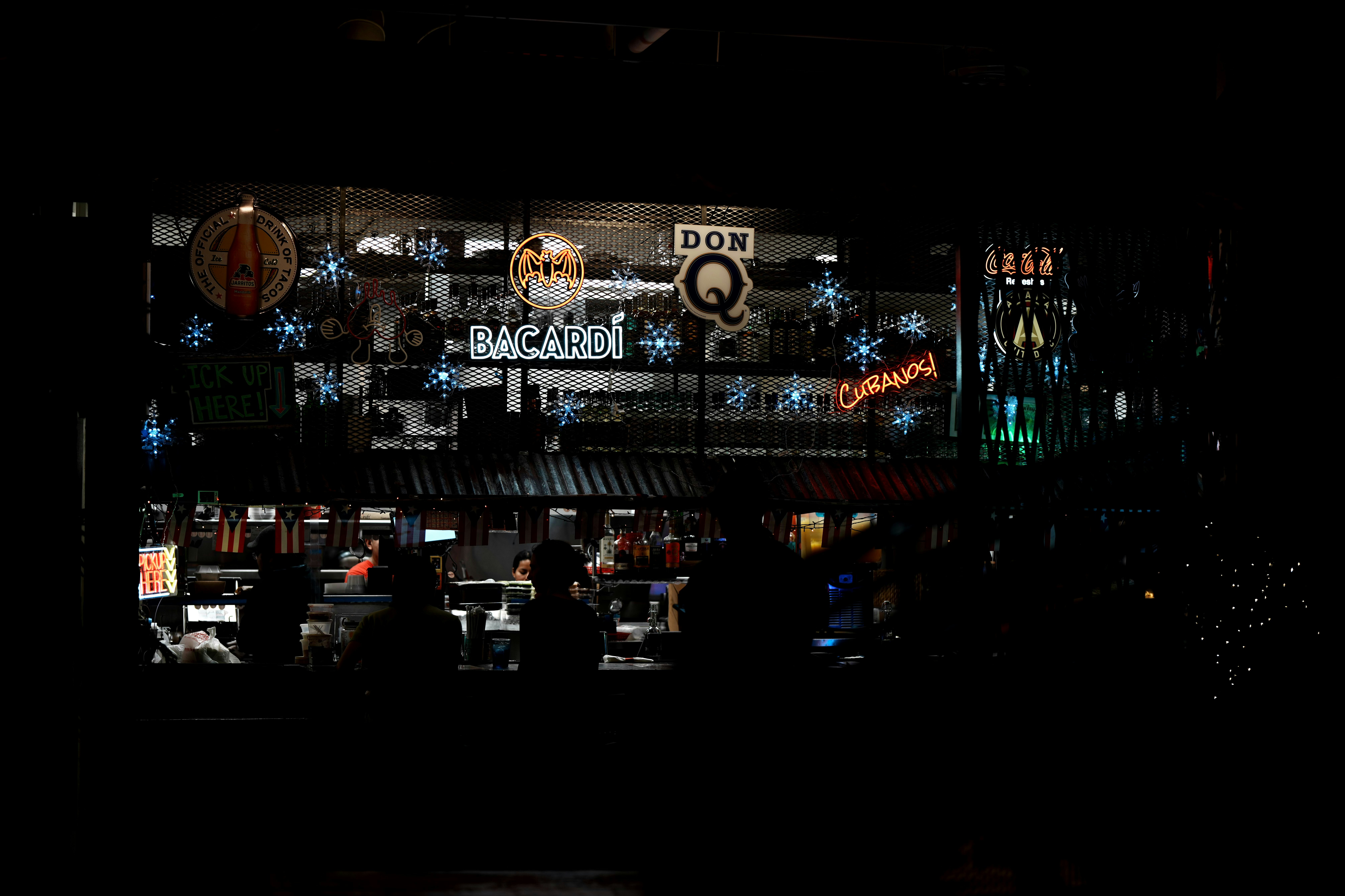 Neon silhouettes at a dimly lit bar window