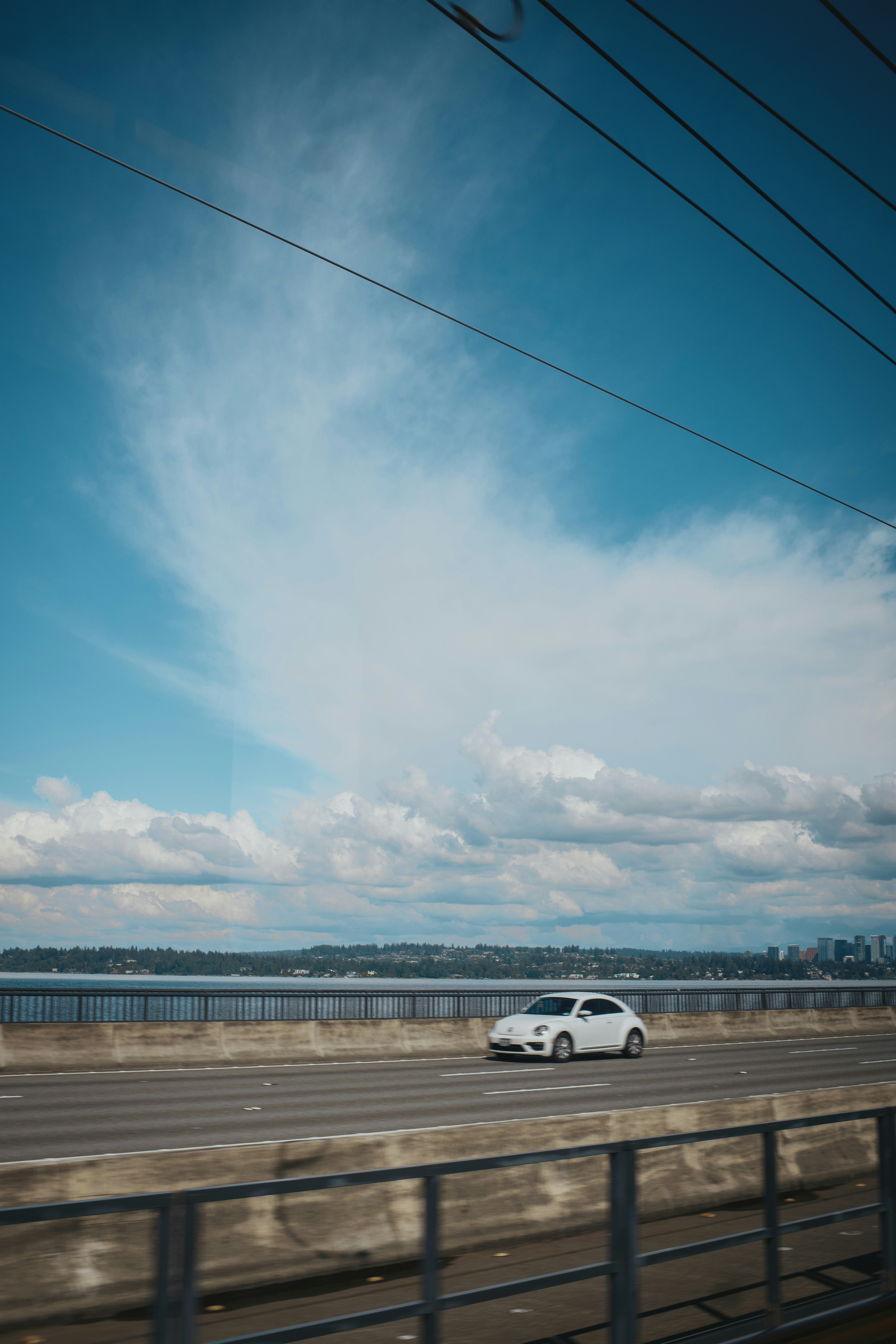 White car on a coastal highway beneath a vast sky