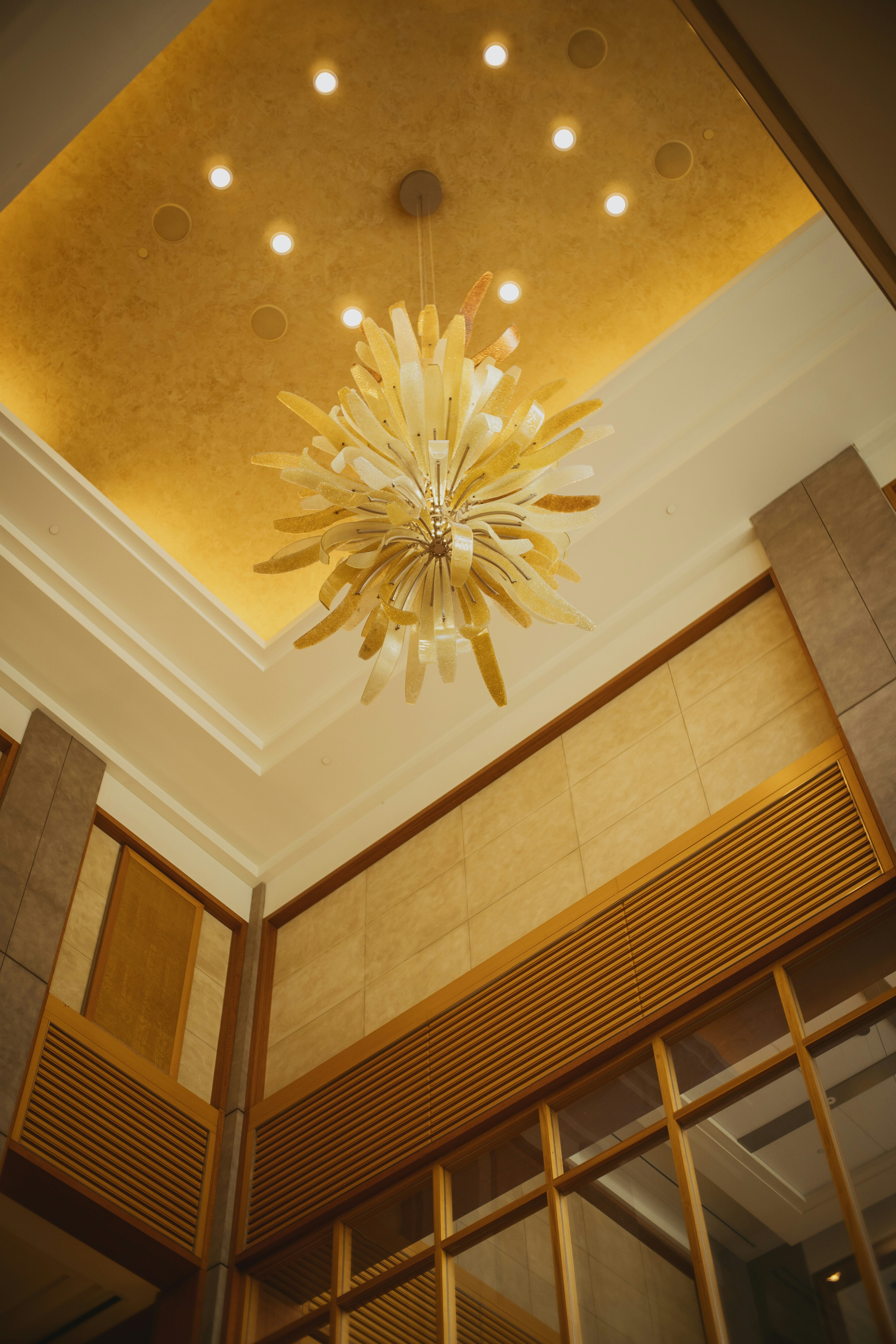 Chandelier Above a Sunlit Atrium: Warm Architecture and Skyward Light