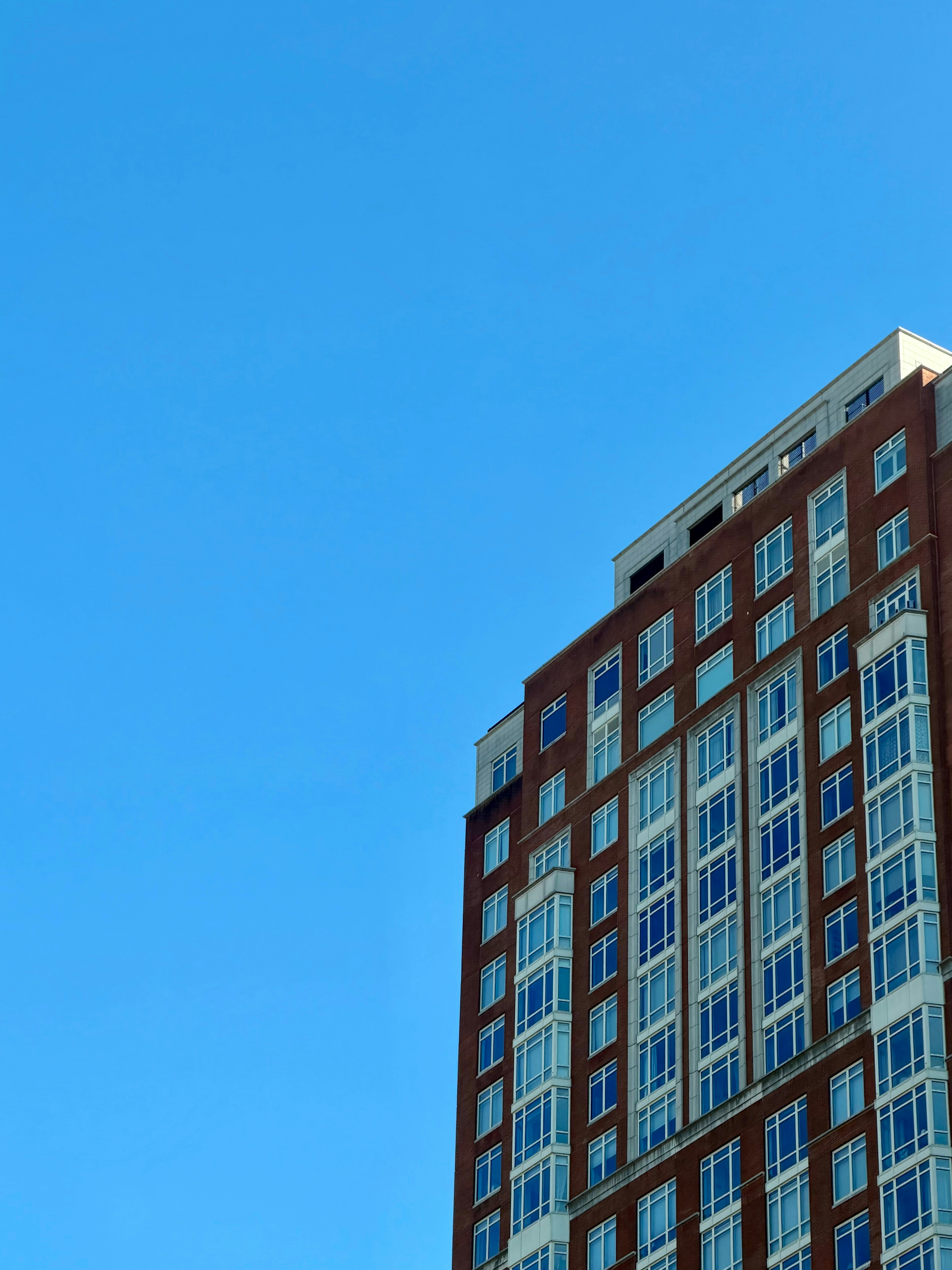Cornered Sky and Brick: A Leaning Urban Facade Reaching for the Blue
