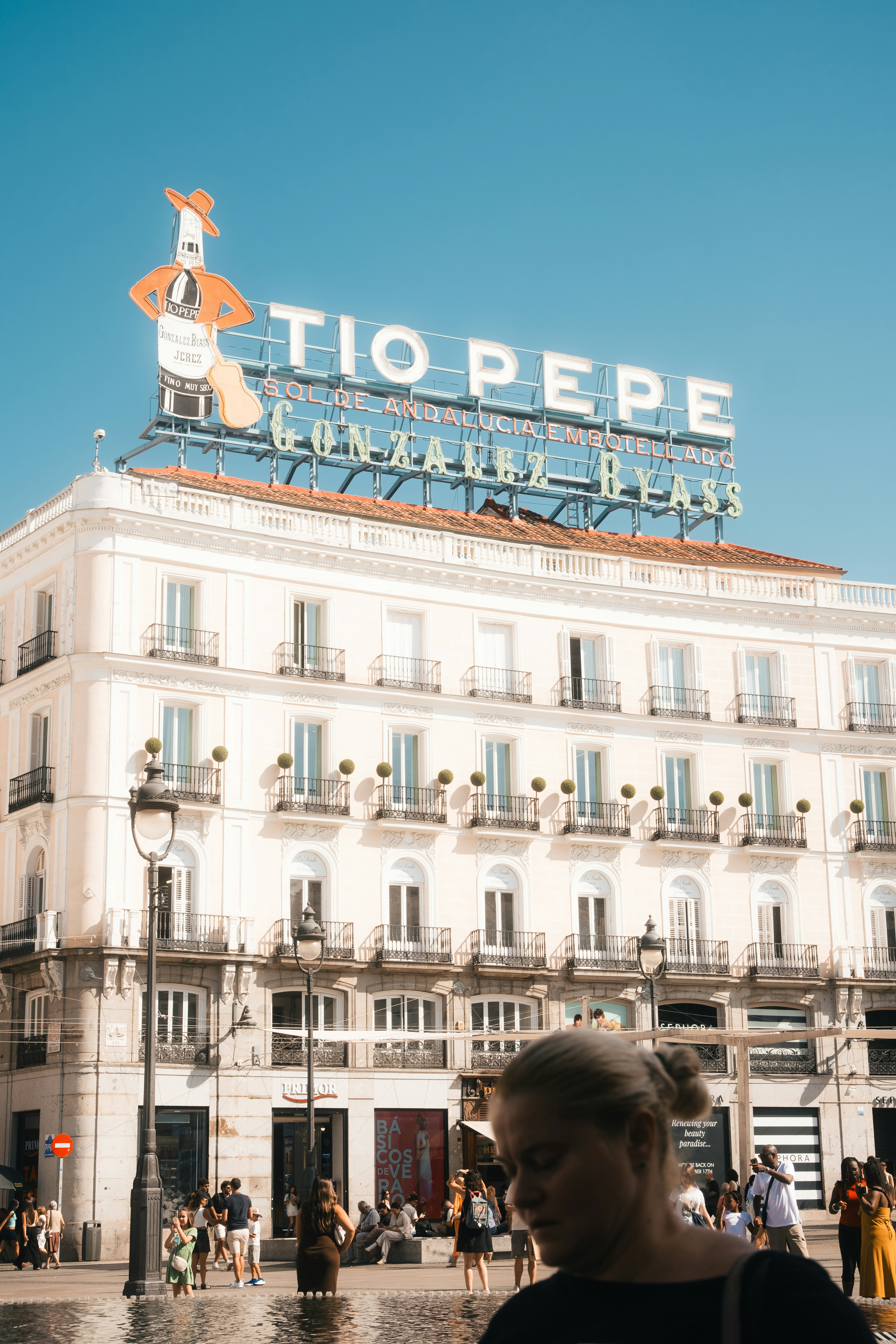Sunlit Facade and Moving Crowd Under Neon Sign in a European Square