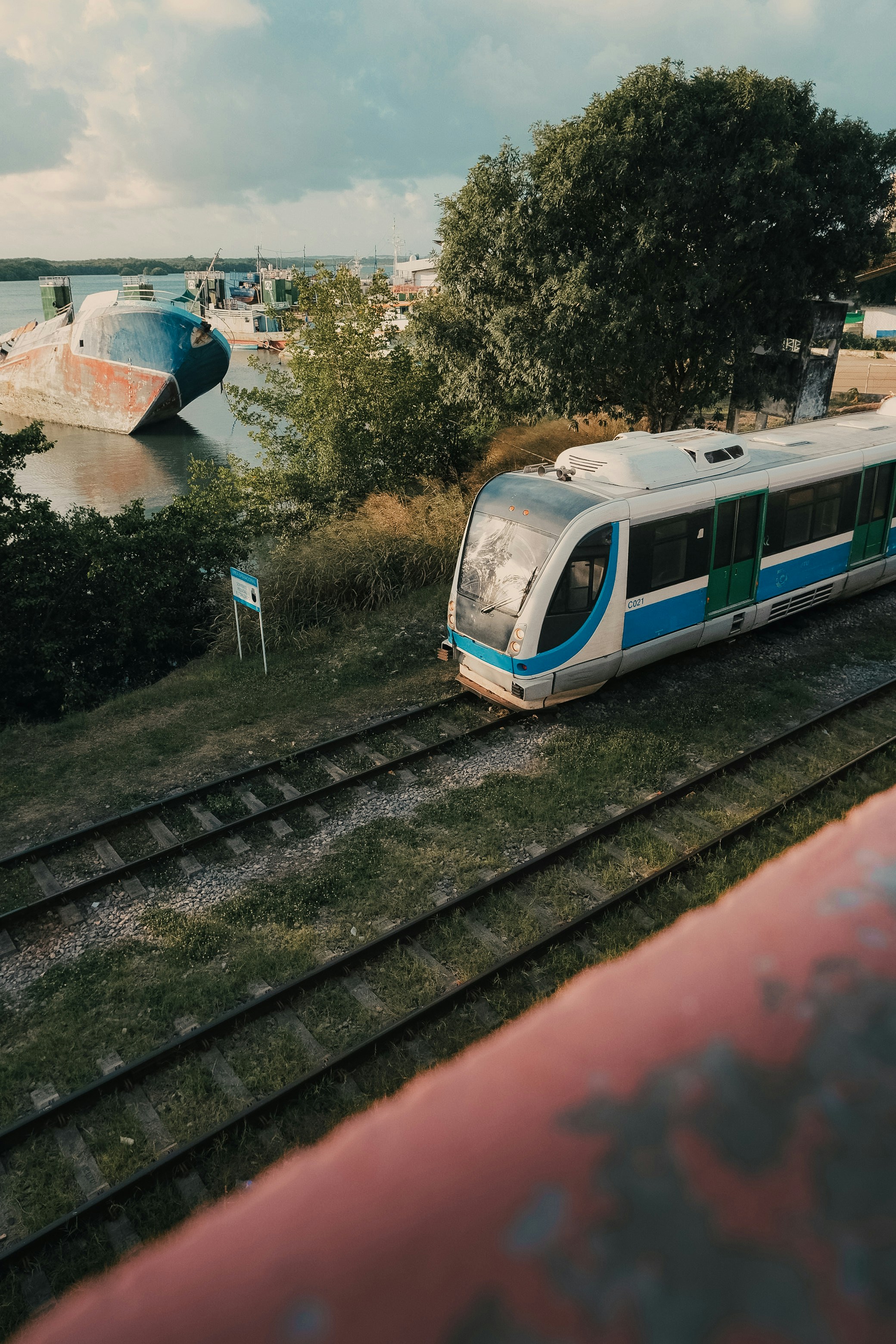Blue and white commuter train at a riverside rail yard