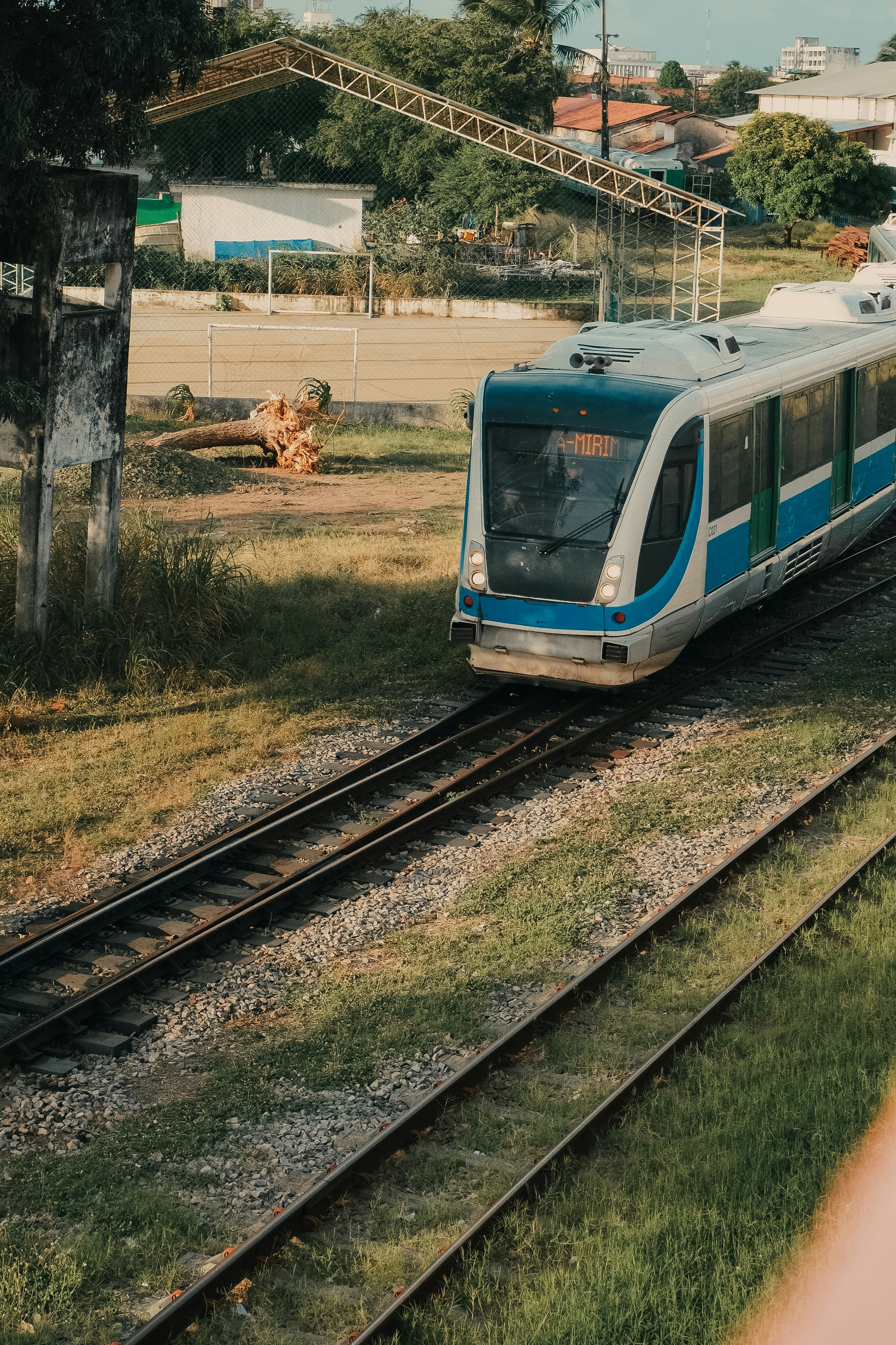 Blue Commuter on the Rails: A Narrow Cut through the Suburban Yard