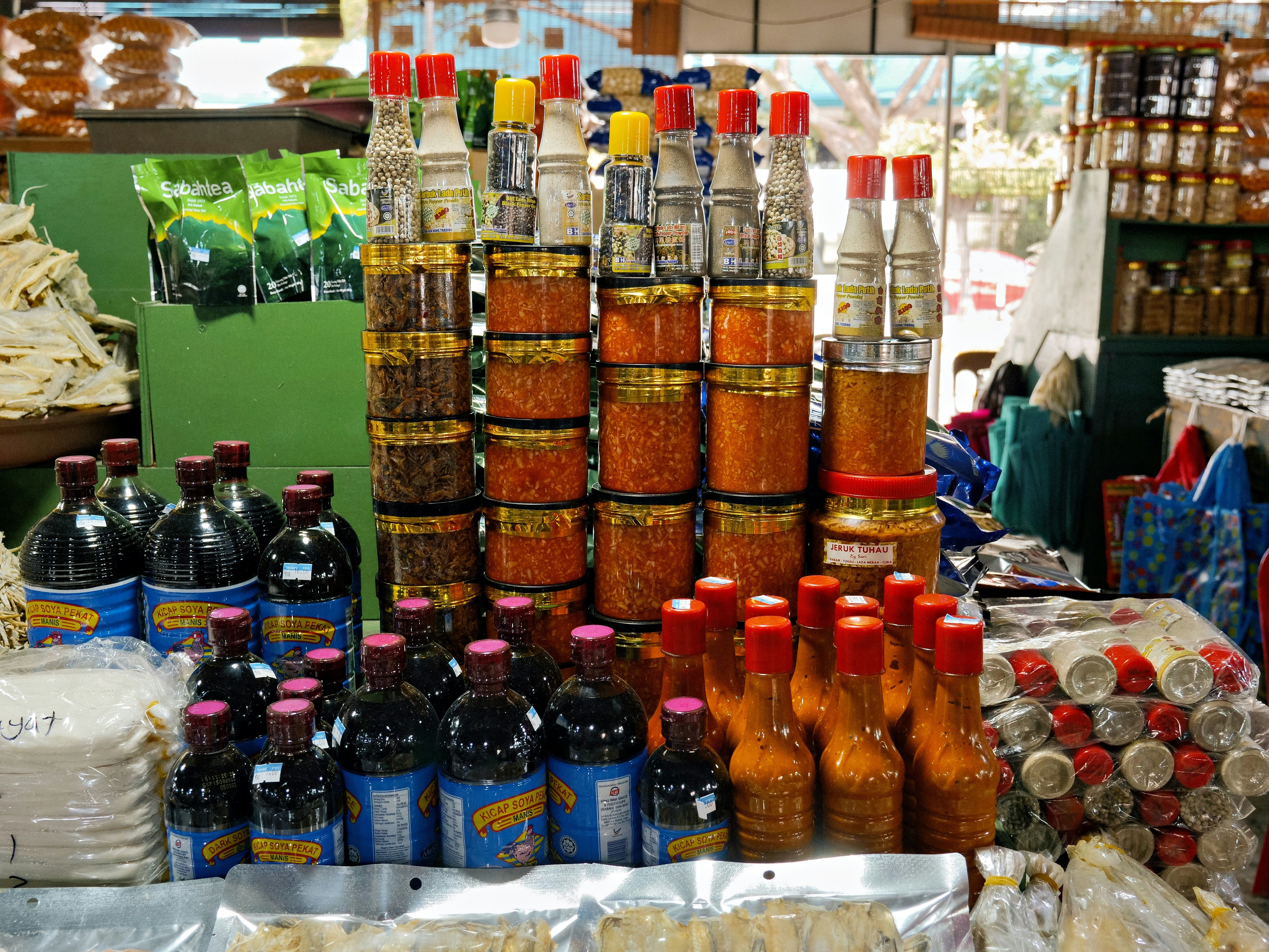 Stacks of spicy sauces dominate a bustling street market stall