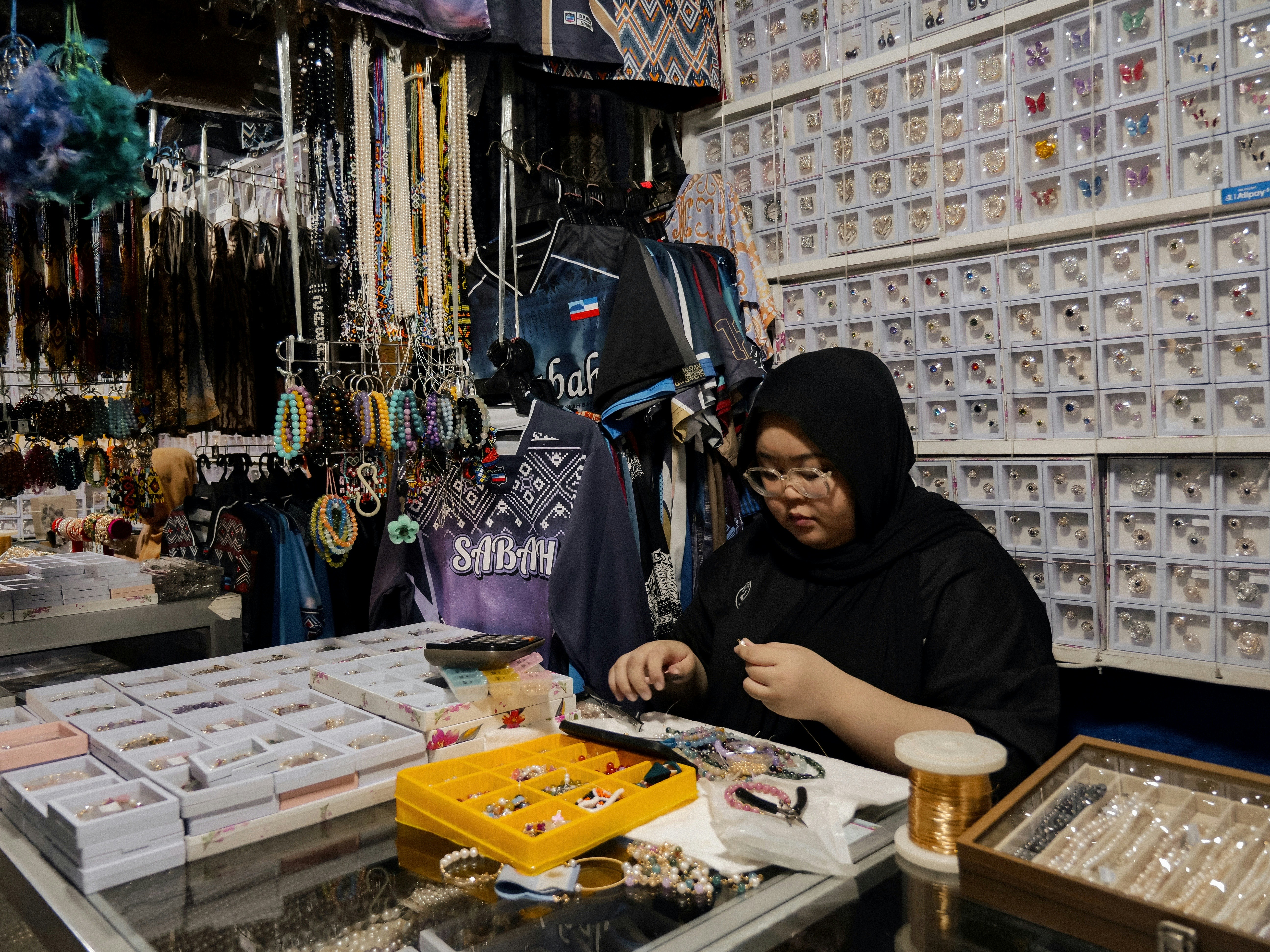 Craftsman at the Counter: Intricate Jewelry Making in a Market Stall