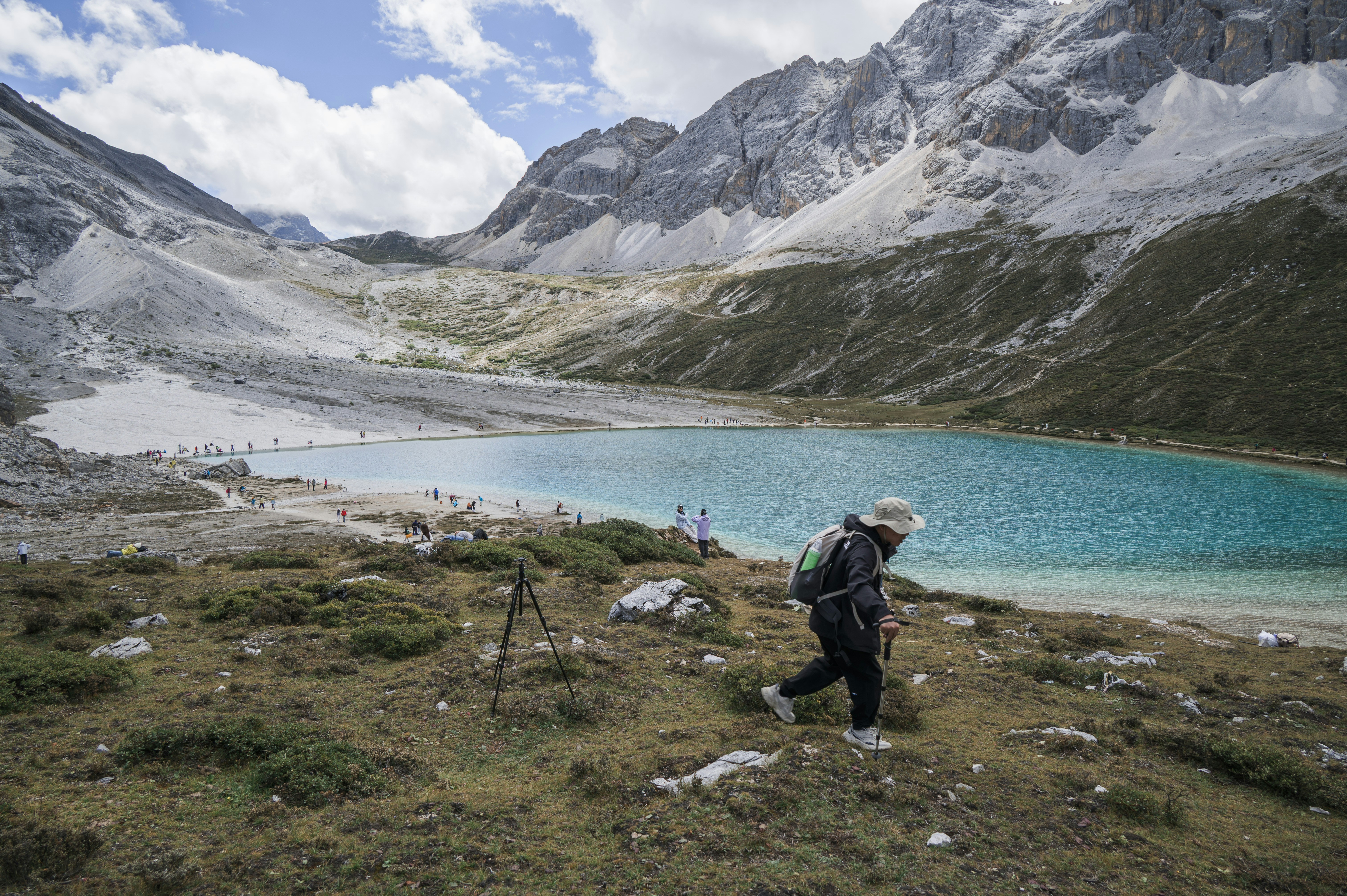 Hiker Crossing Turquoise Tarn Below Jagged Peaks