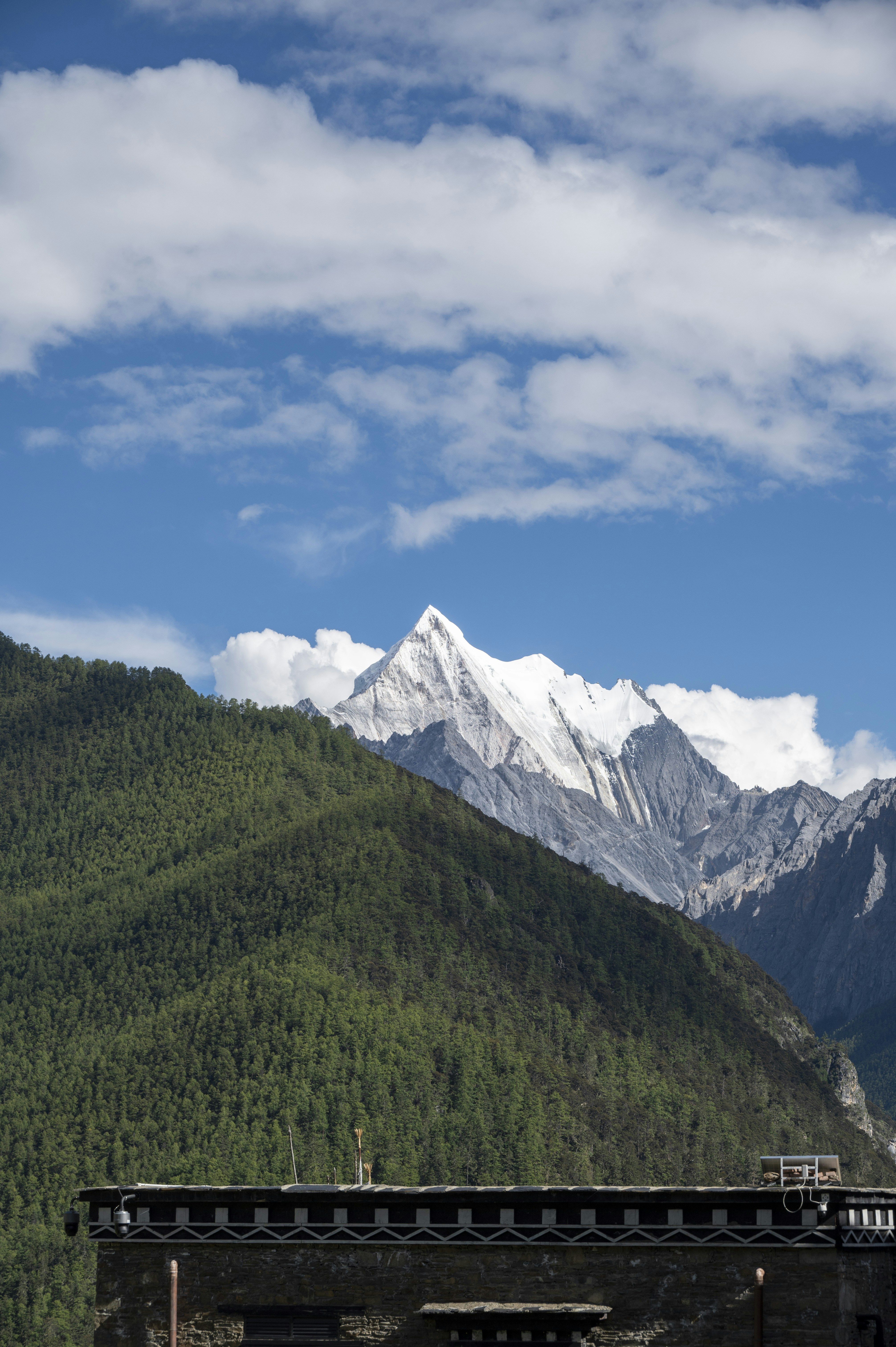 Snow-capped Peak Rising Behind Pine-clad Slopes Over a Merries Stone Terrace
