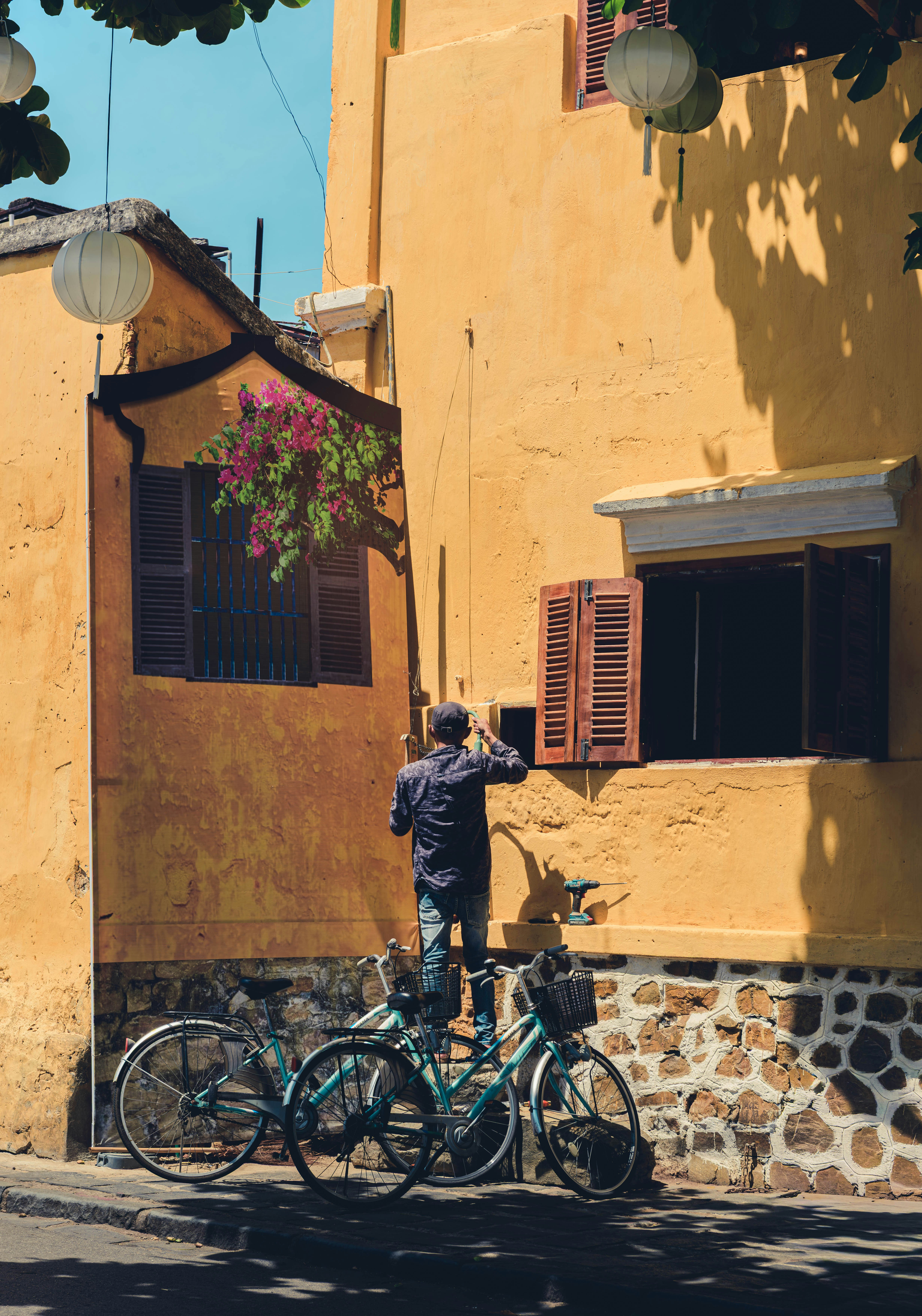 Sunlit Yellow Facade and a Curious Gardener in the Alley