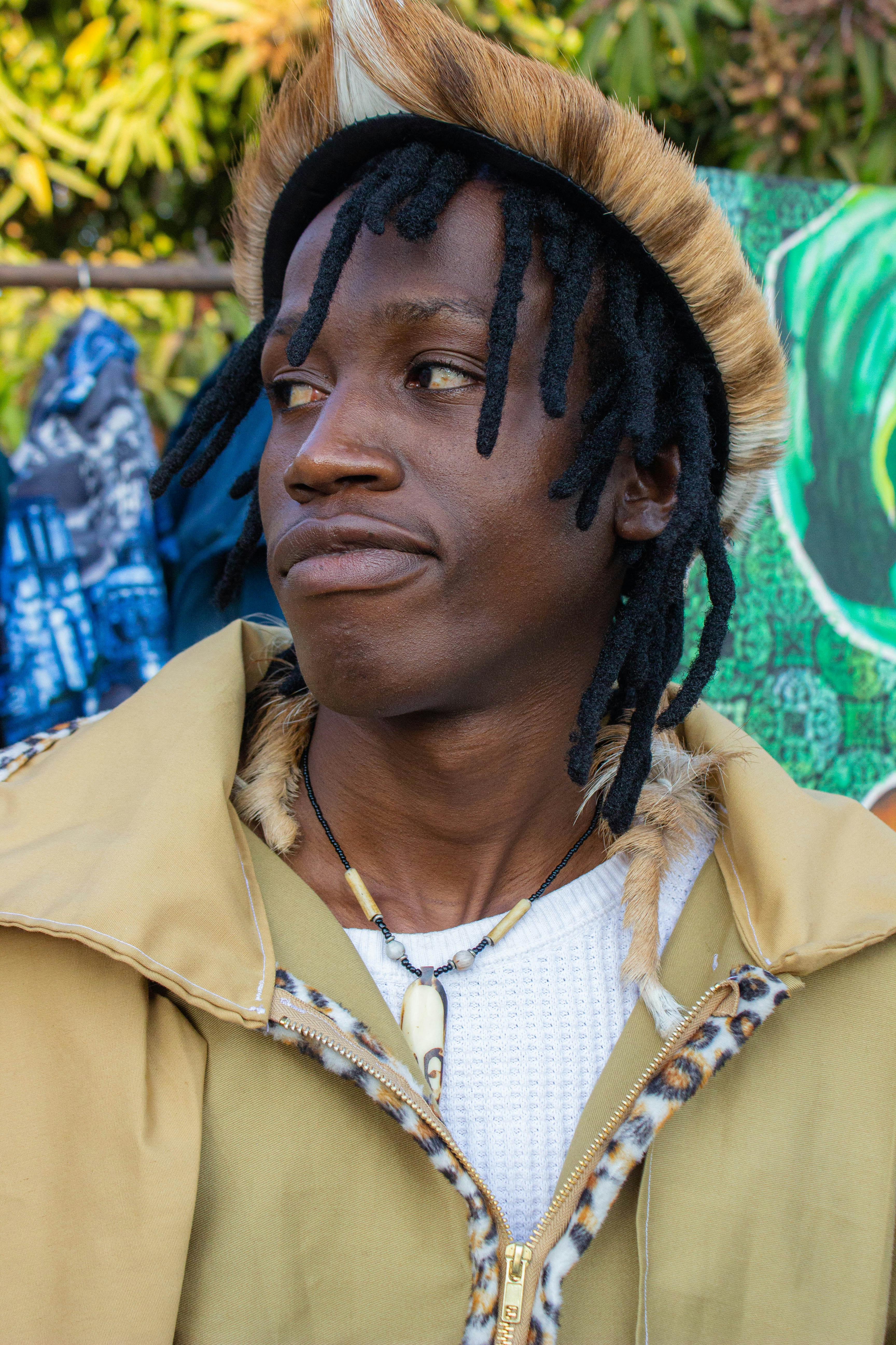 Portrait beneath a fur-lined hood against a graffiti backdrop