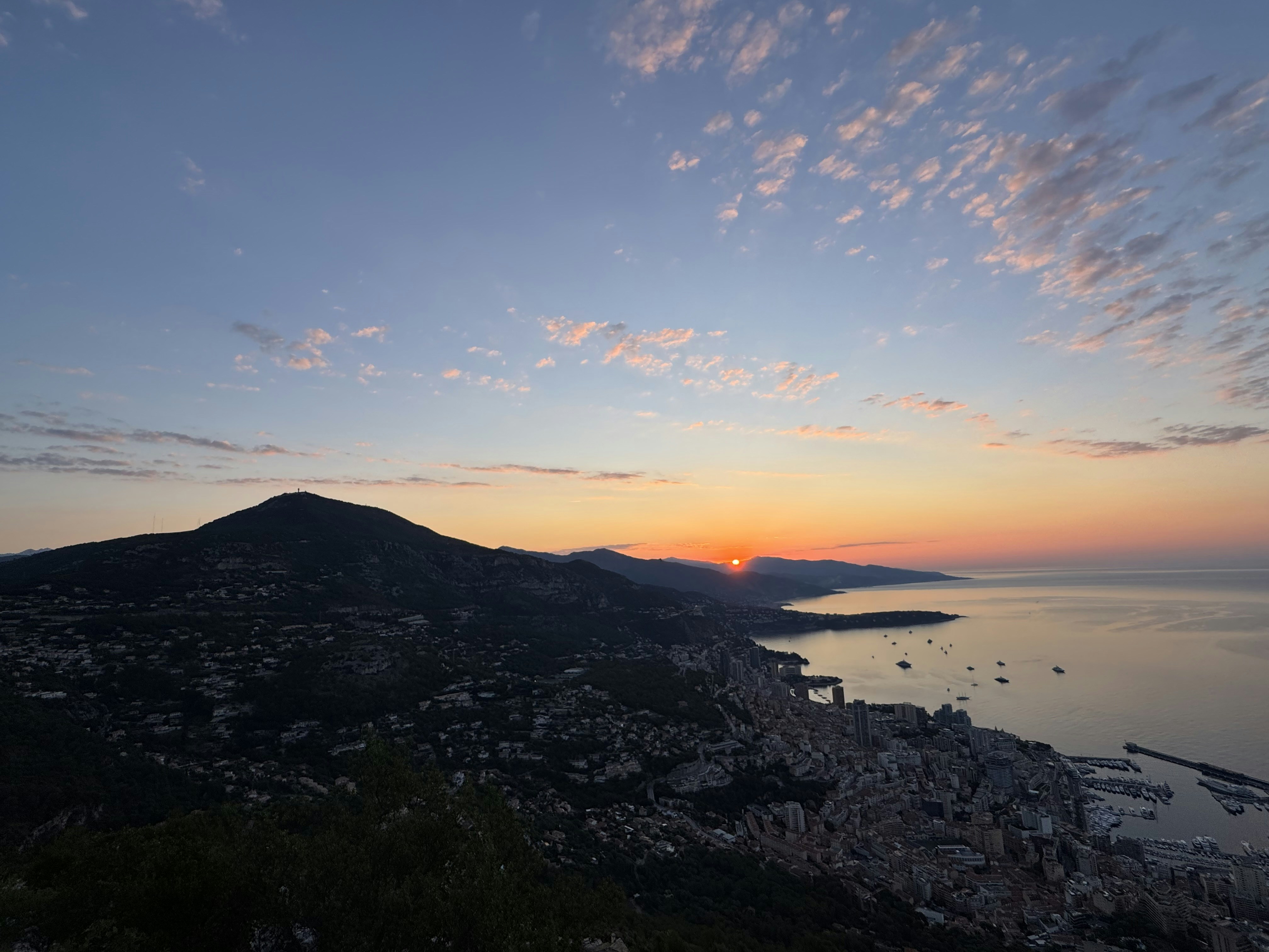 Sunset Over the Crescent Coast: town and harbor tucked beneath a silhouetted promontory