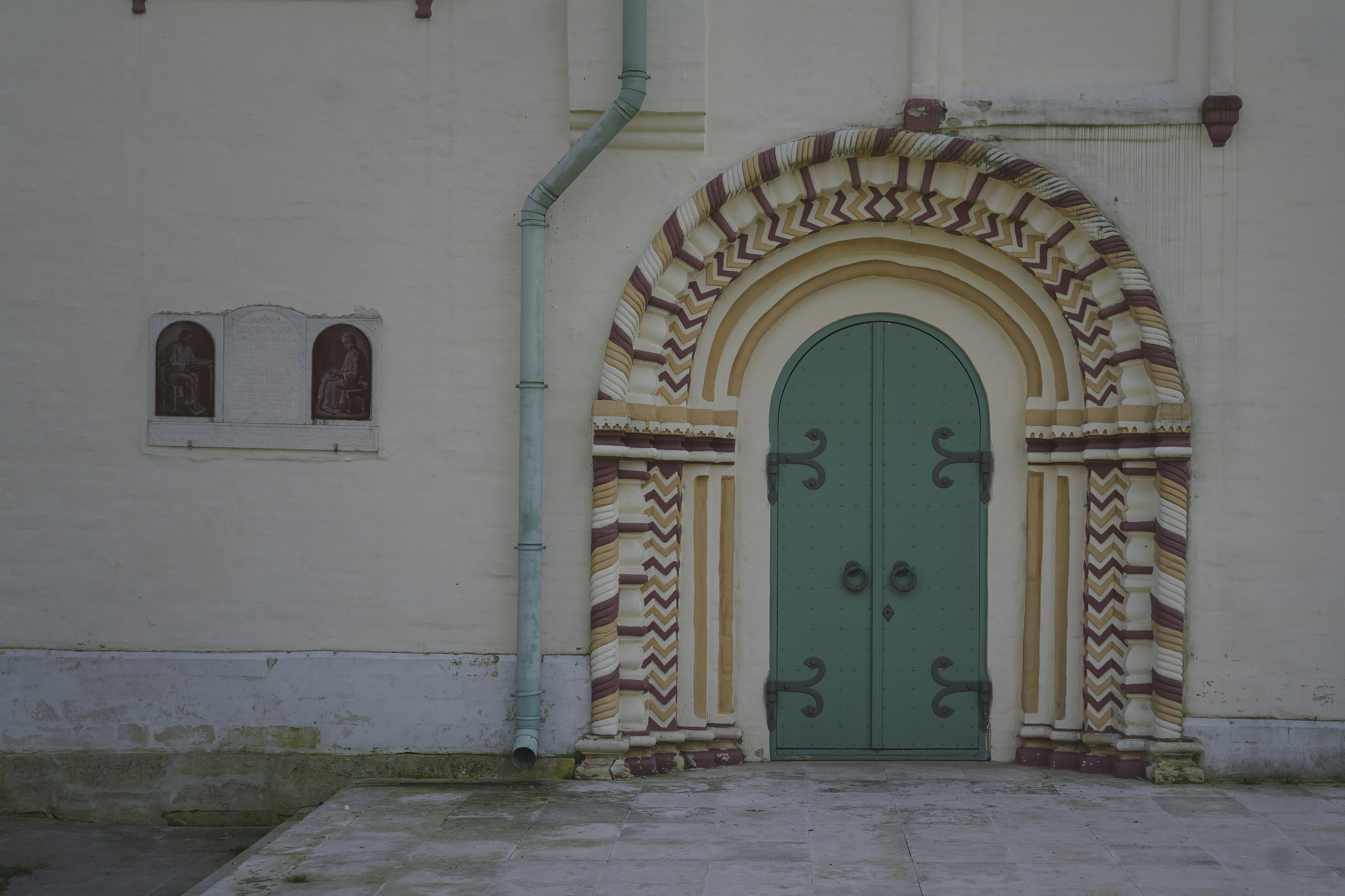 Green door with ornamental archway in pale facade