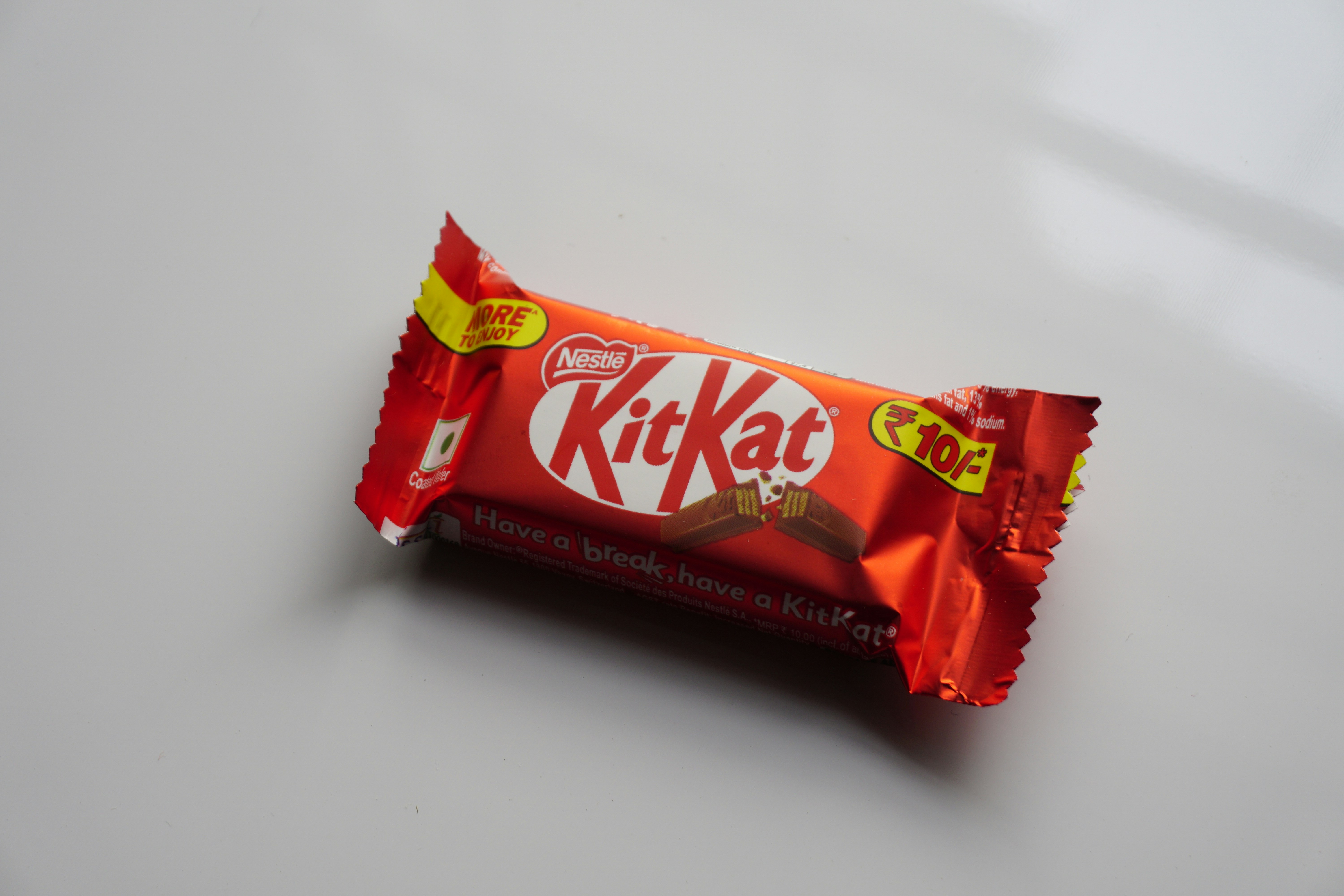 Crinkled Cadence: KitKat Lie of Red Packaging on a Soft White Surface