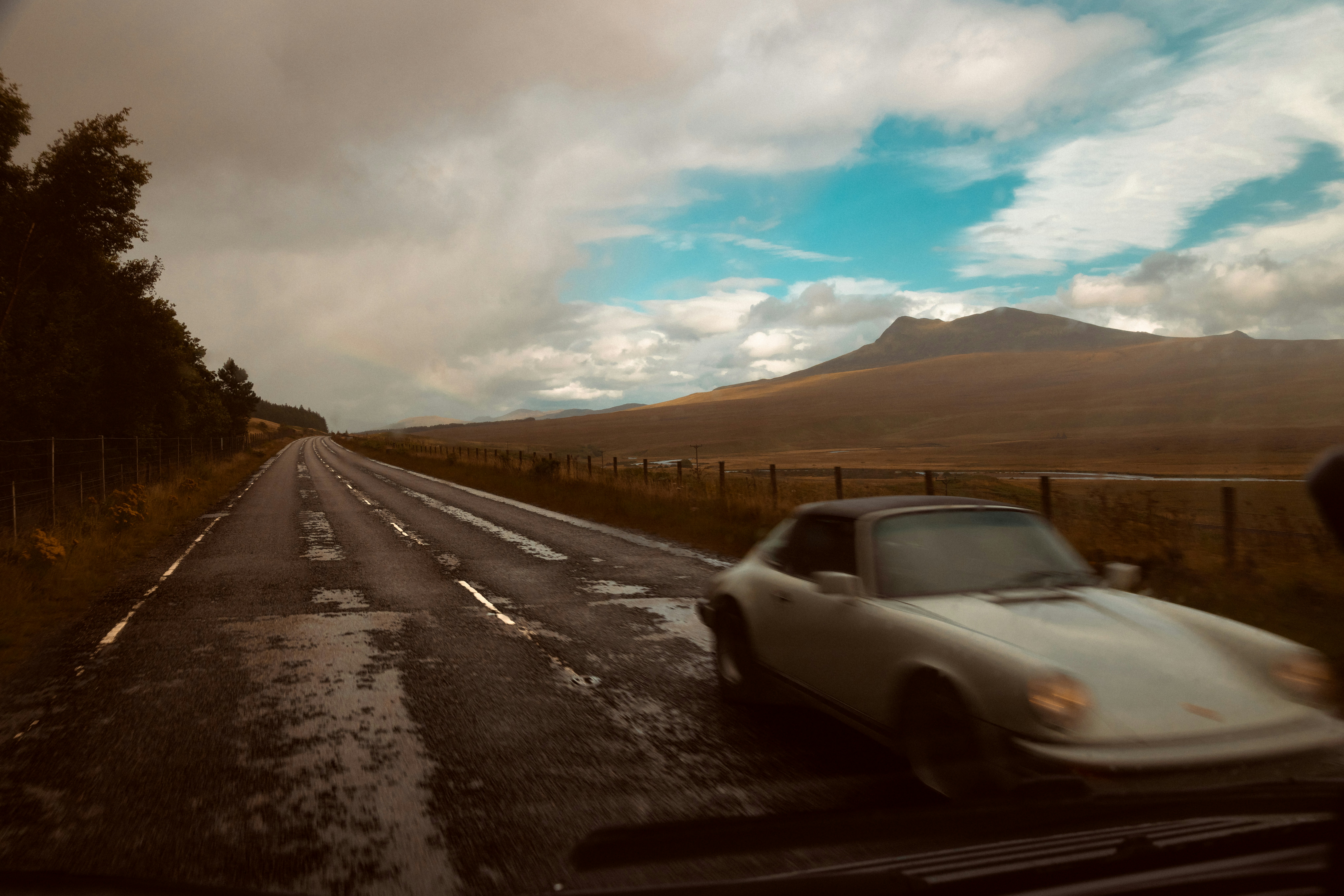 A Cresting Highland Road: Car Blur on a Moored Horizon