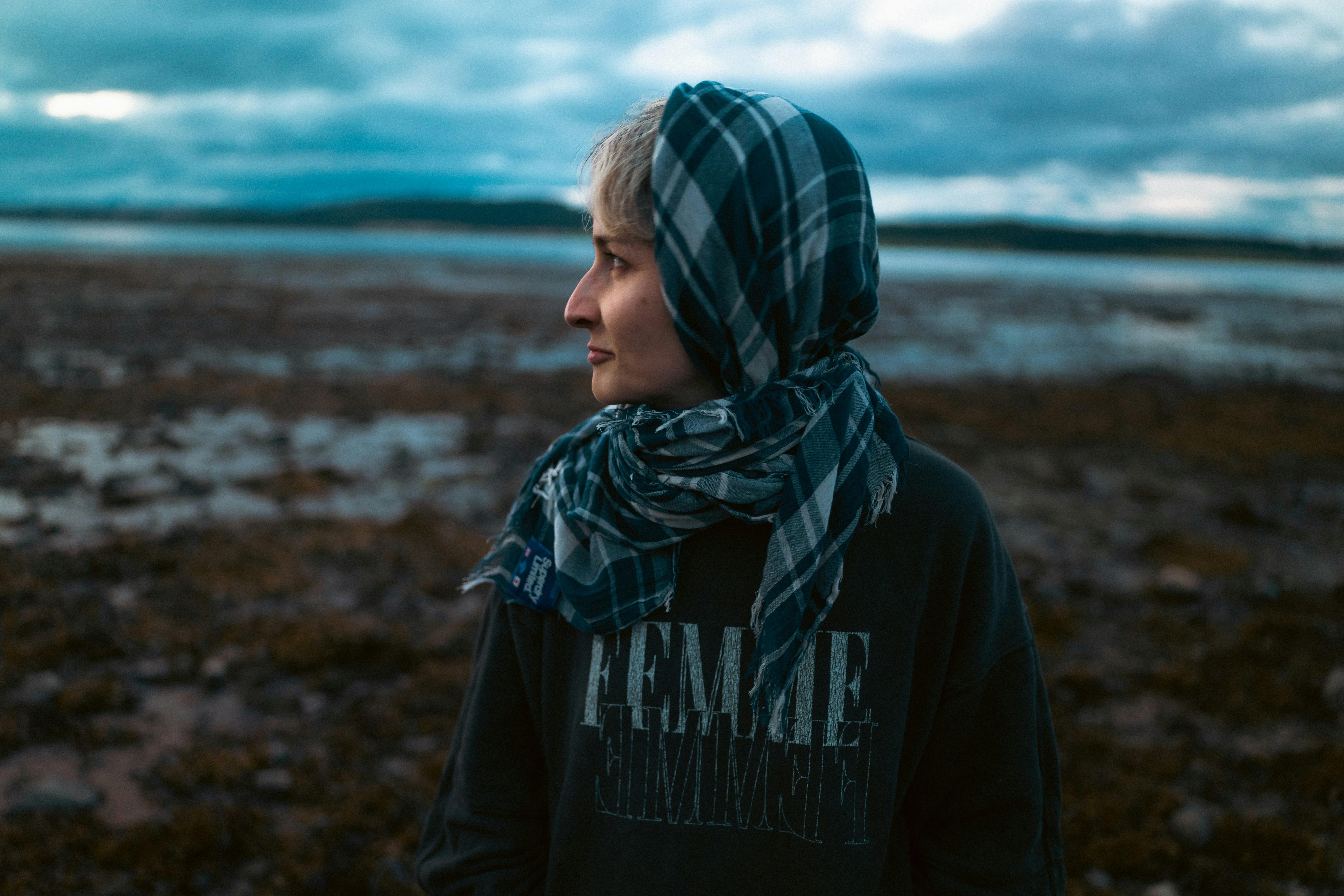 Portrait in Wind: A woman in a blue scarf gazes toward the horizon