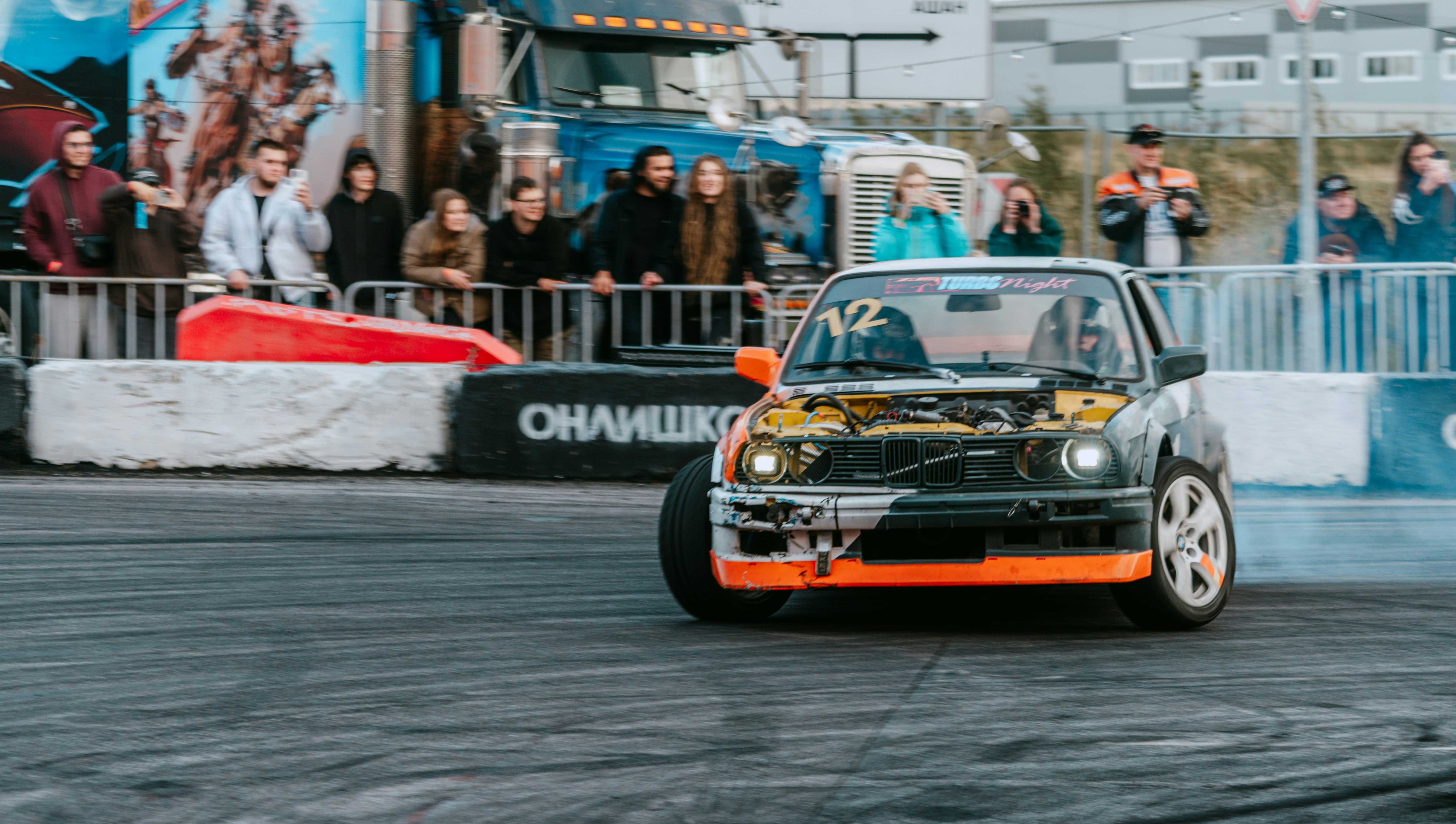 Orange-fronted Drift: A Car Screws Through a Ring of Enthusiasts