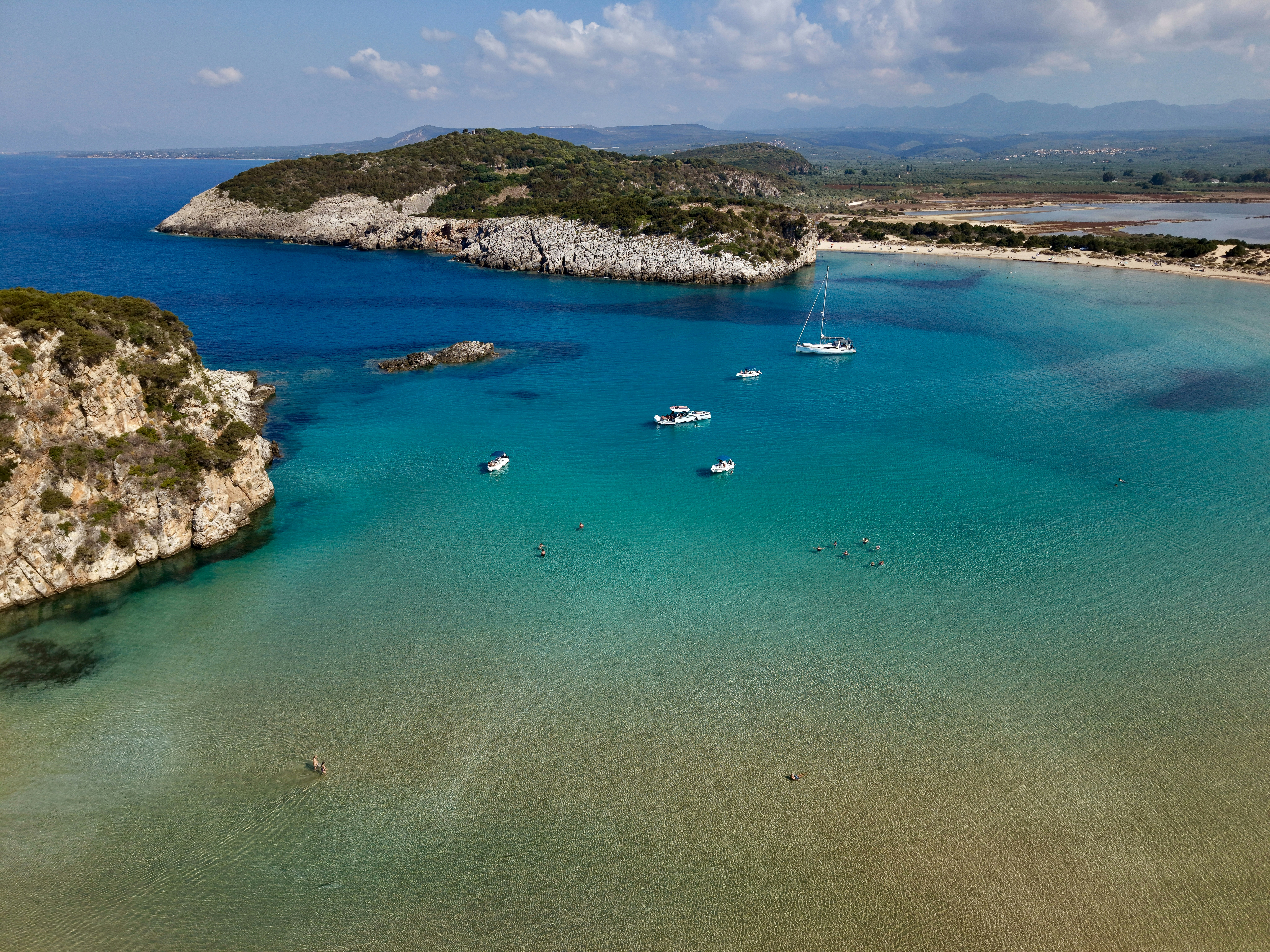 Aerial view of boats in the turquoise waters of Voidokilia Beach in Greece