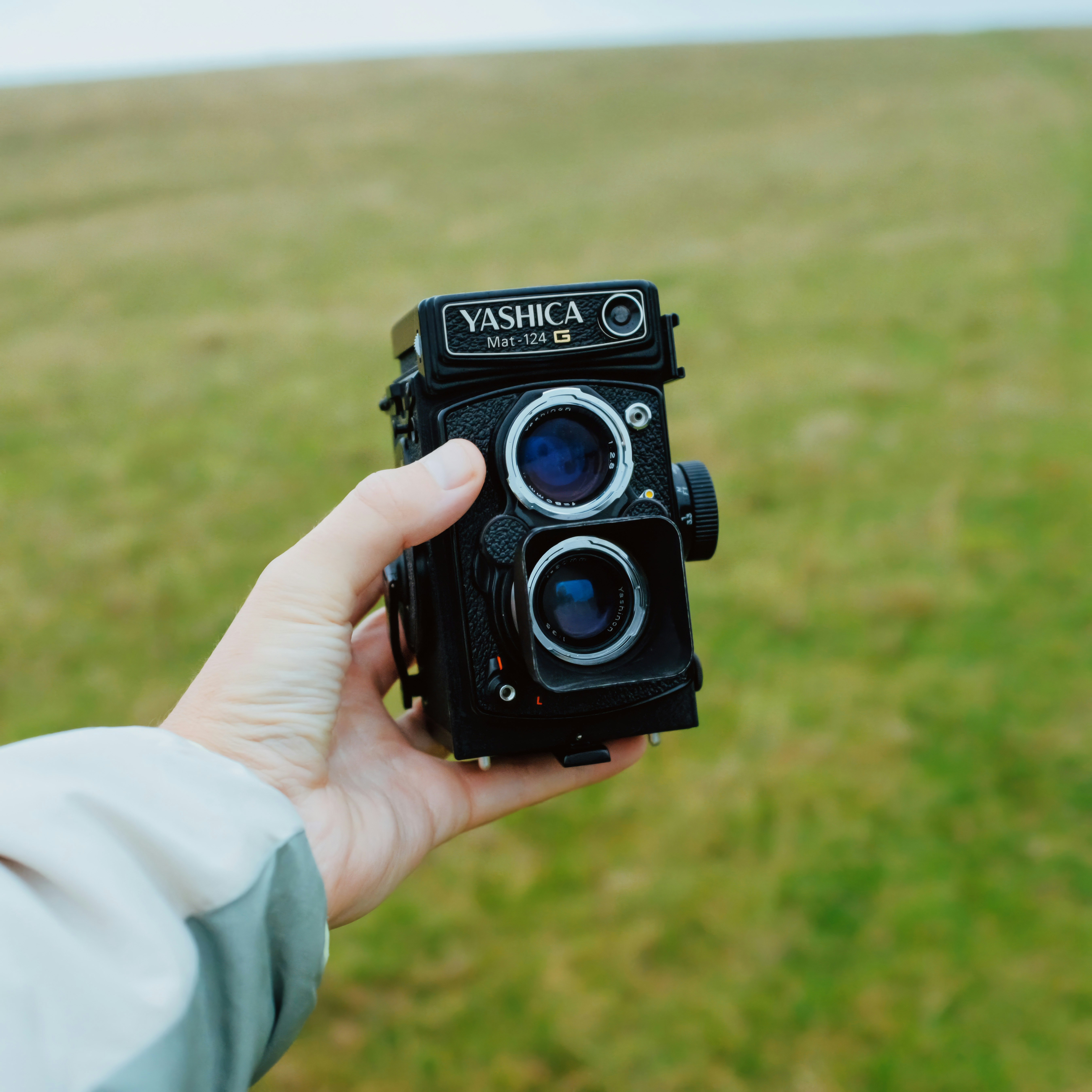 Handheld Yashica: A Vintage Viewfinder in a Green Field