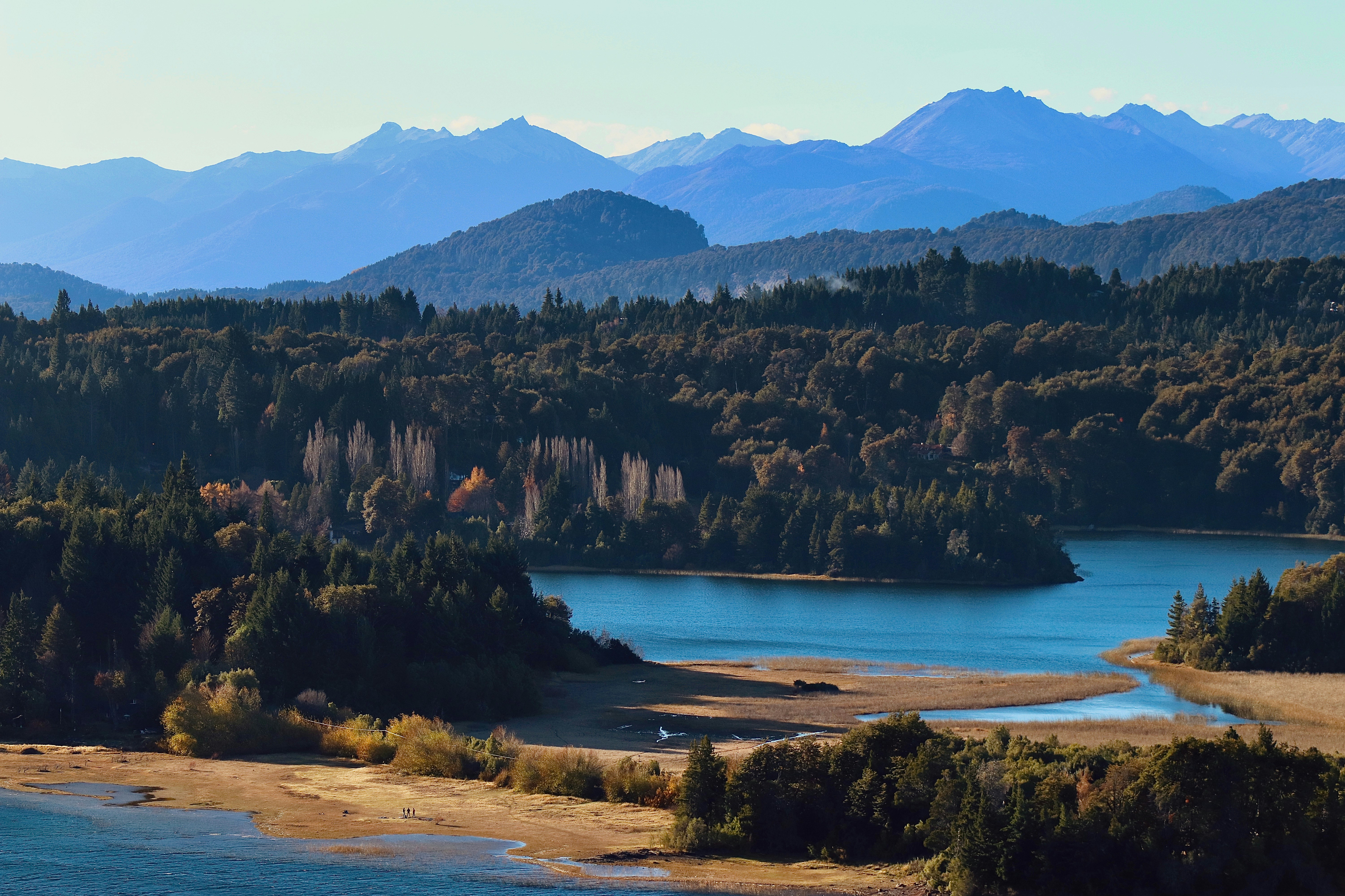 Serene Mountain Return: A Ribbon of Lake Between Forested Ridges Under Blue Skies