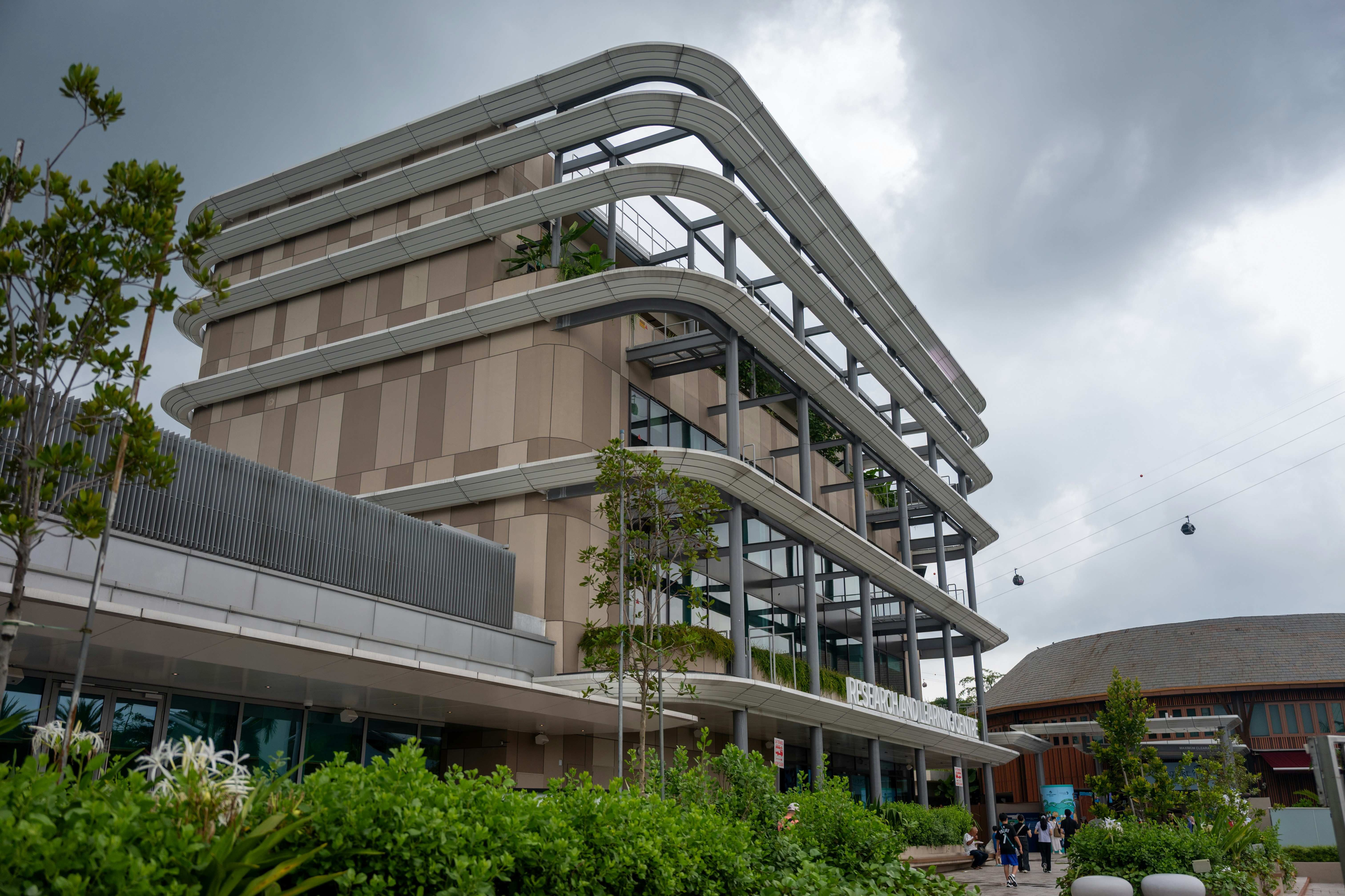 Curved Facade in Motion: A Layered Modern Building with Surrounding Greenery