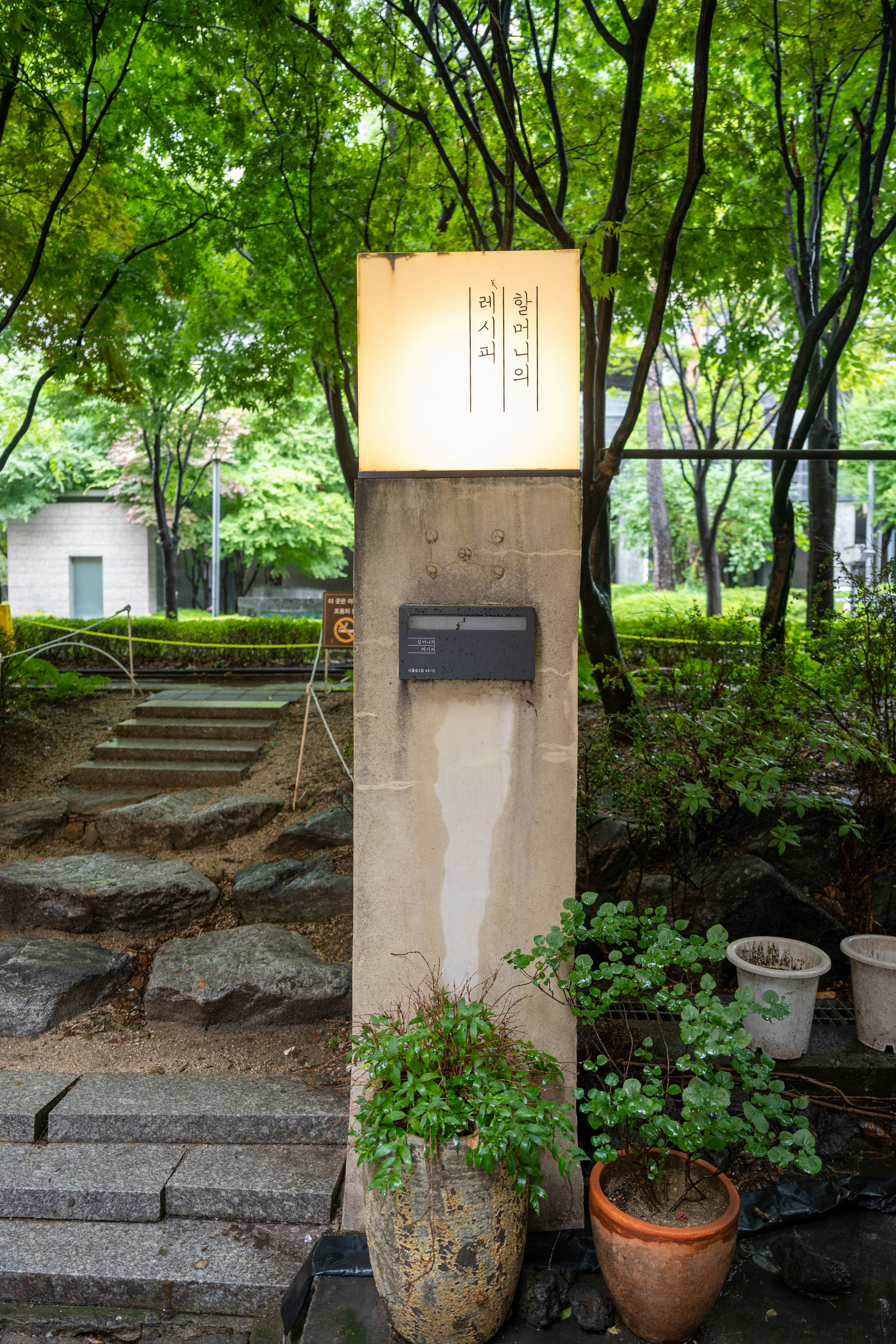 Mediterranean-tinged courtyard pedestal with lit sign and potted greenery