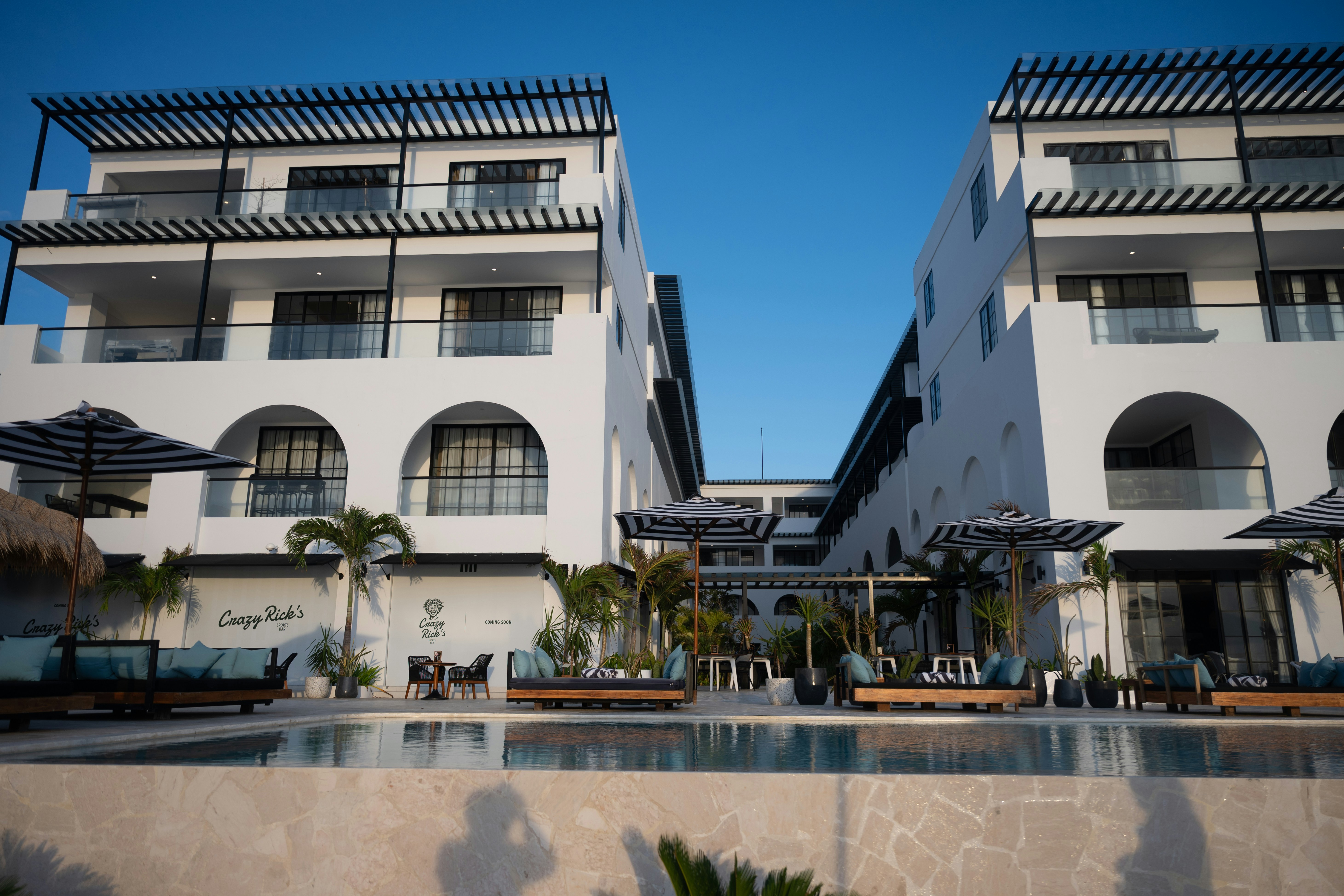 Sunlit Resort Facade Framed by Poolside Loungers