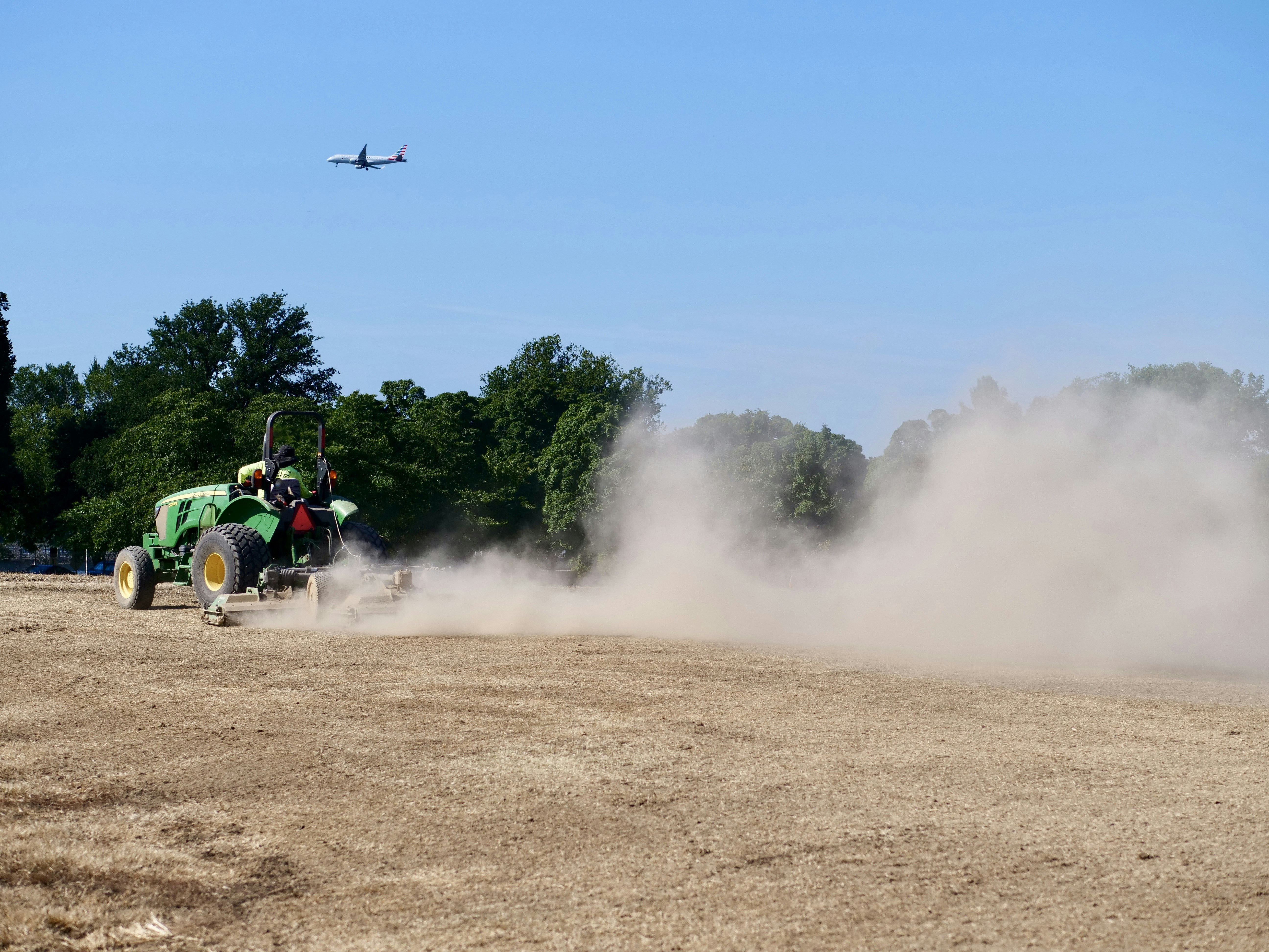 Dust Trail and Tractor in a Sunlit Field