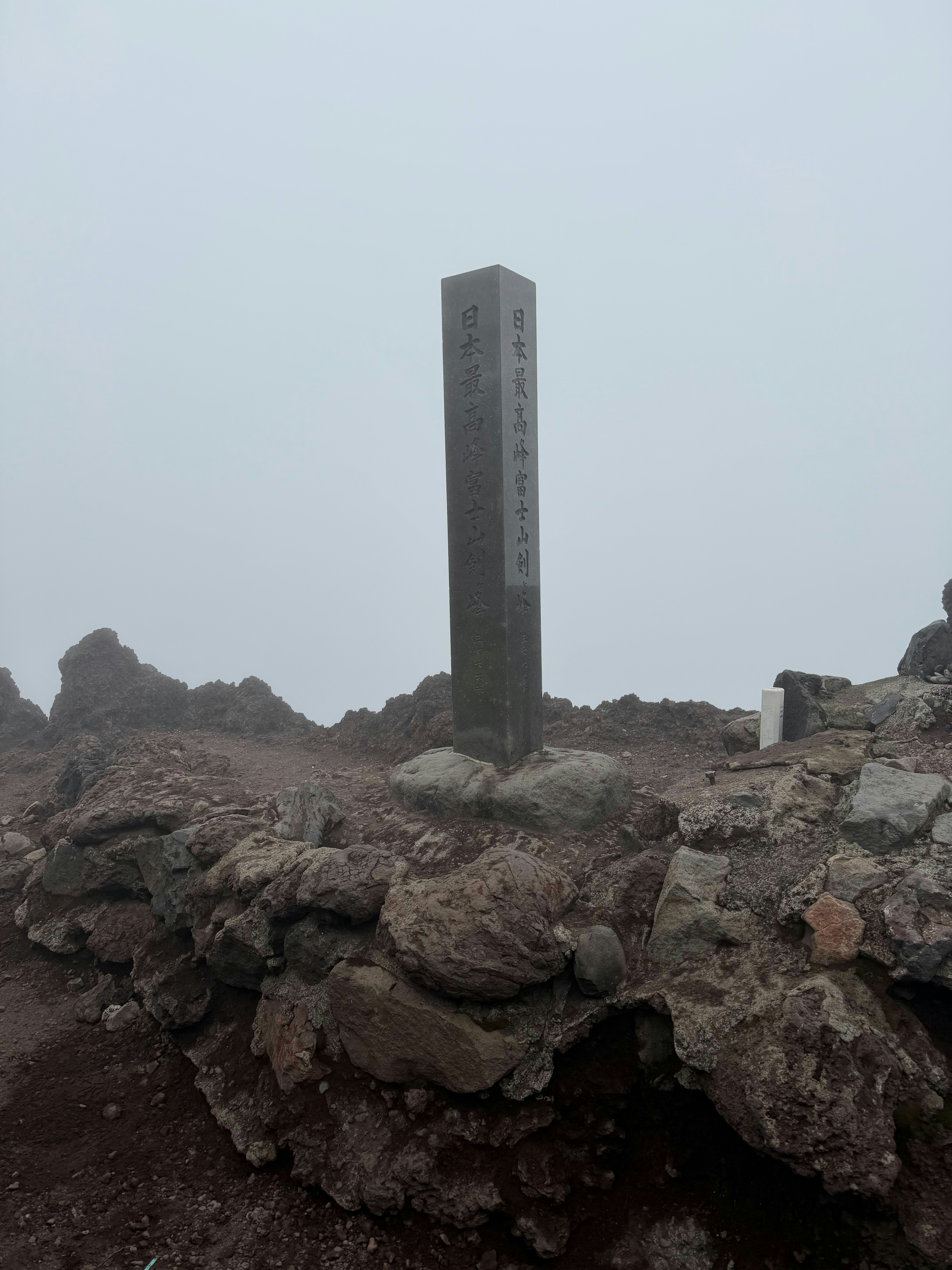 Summit Monument in Mist: A Lone Obelisk on a Rocky Crater